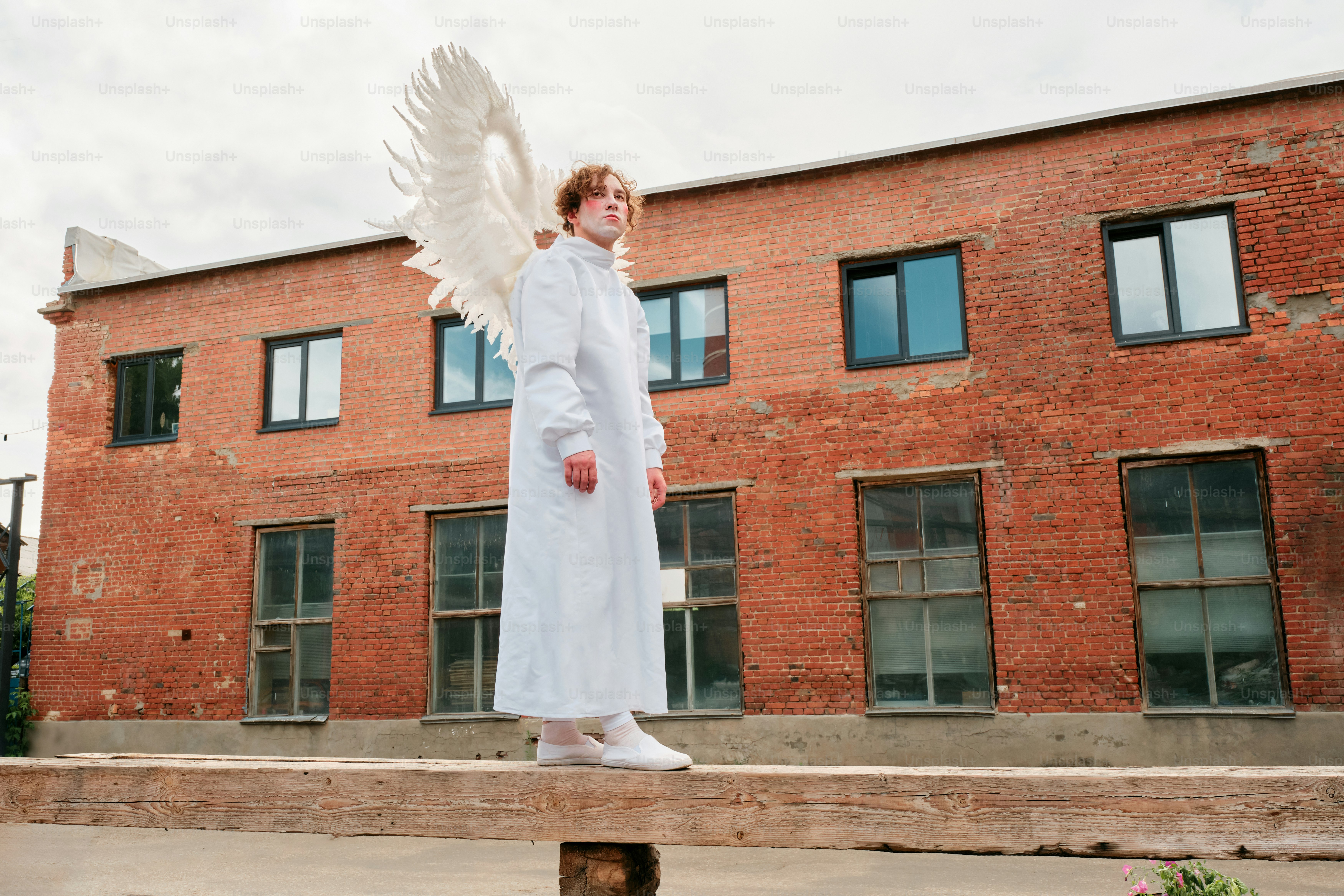 A woman dressed in white standing on a ledge photo – Angel Image on ...