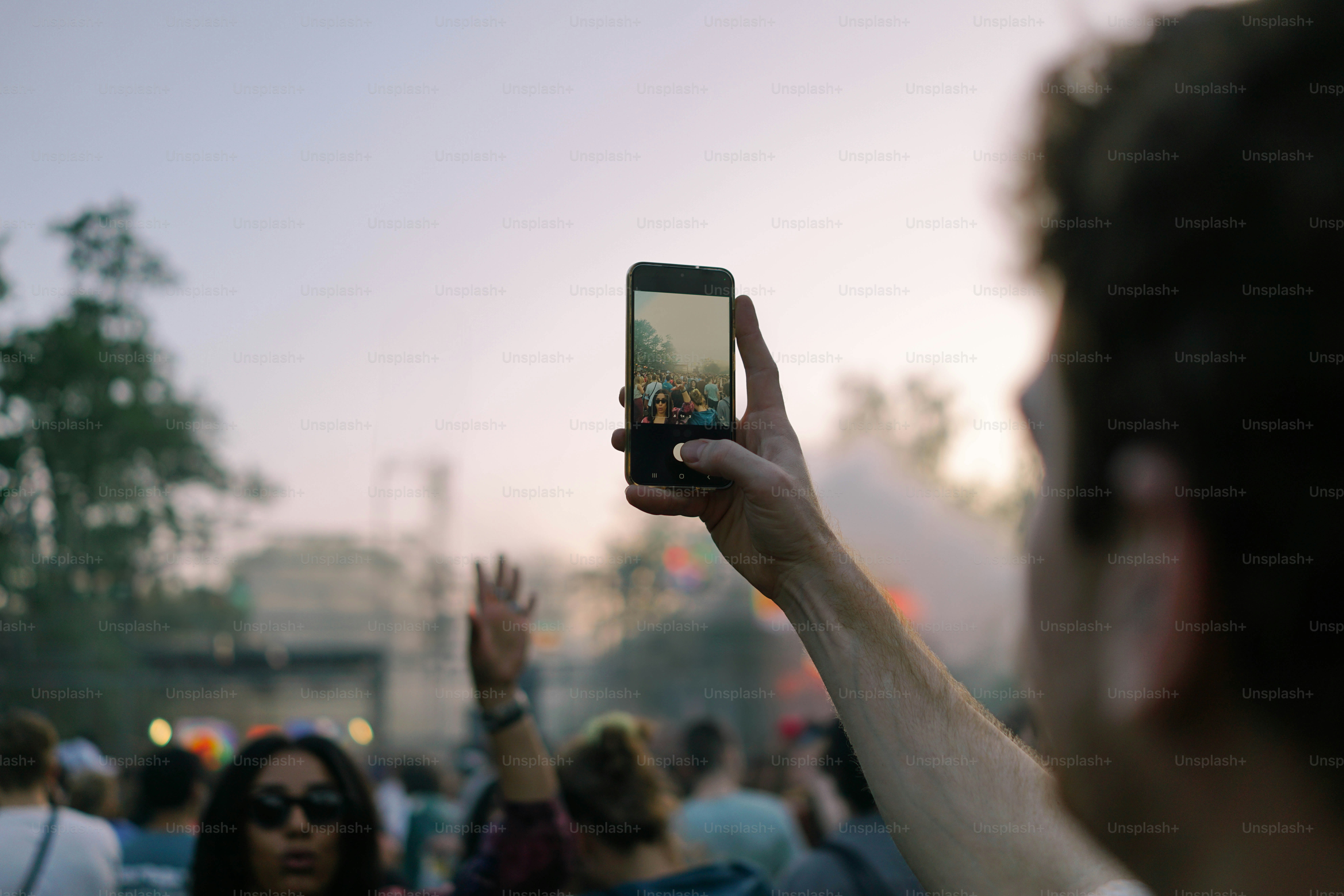A man taking a picture of a crowd with his cell phone photo – Festival ...