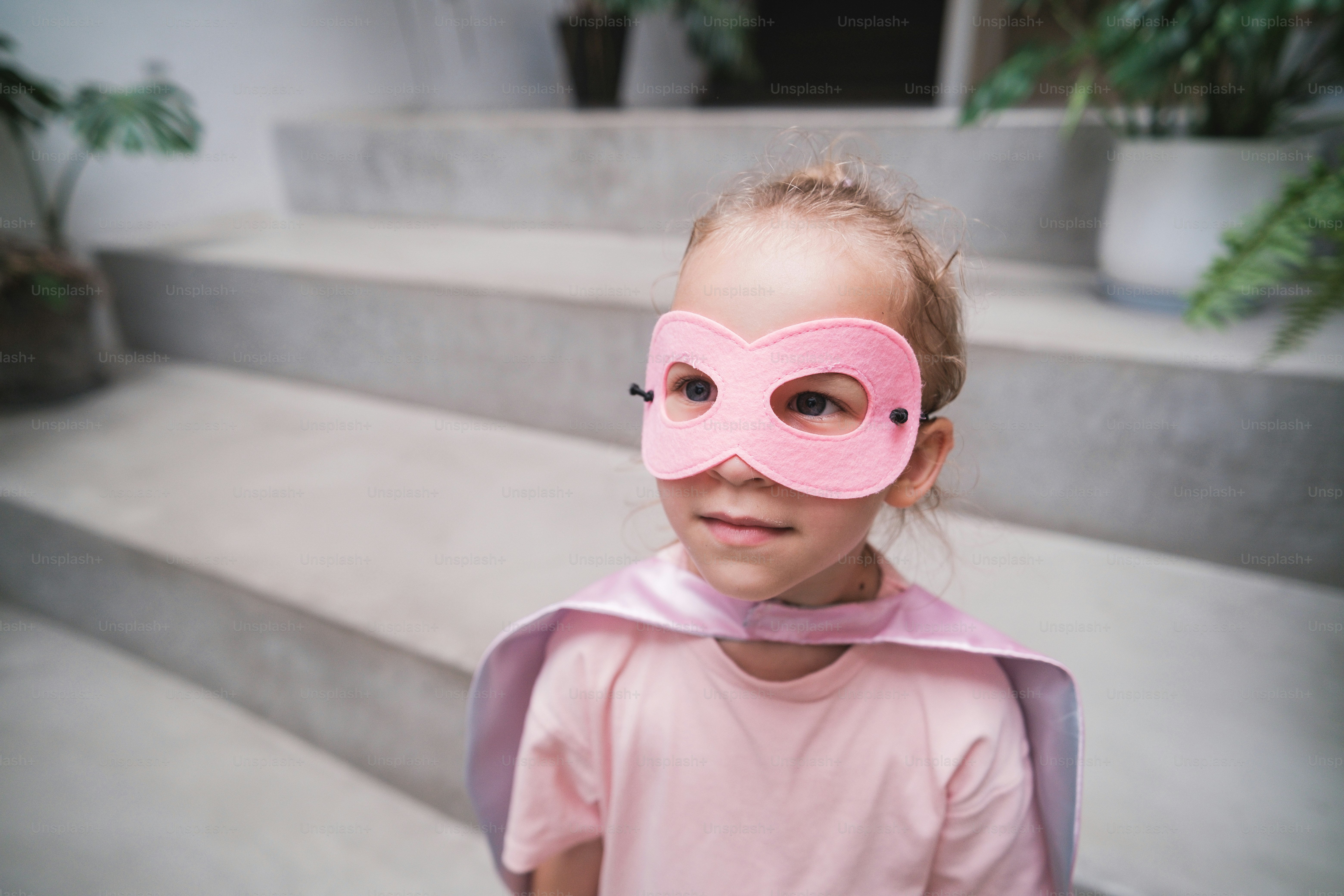A little girl wearing a pink mask and a pink cape photo – Champion ...