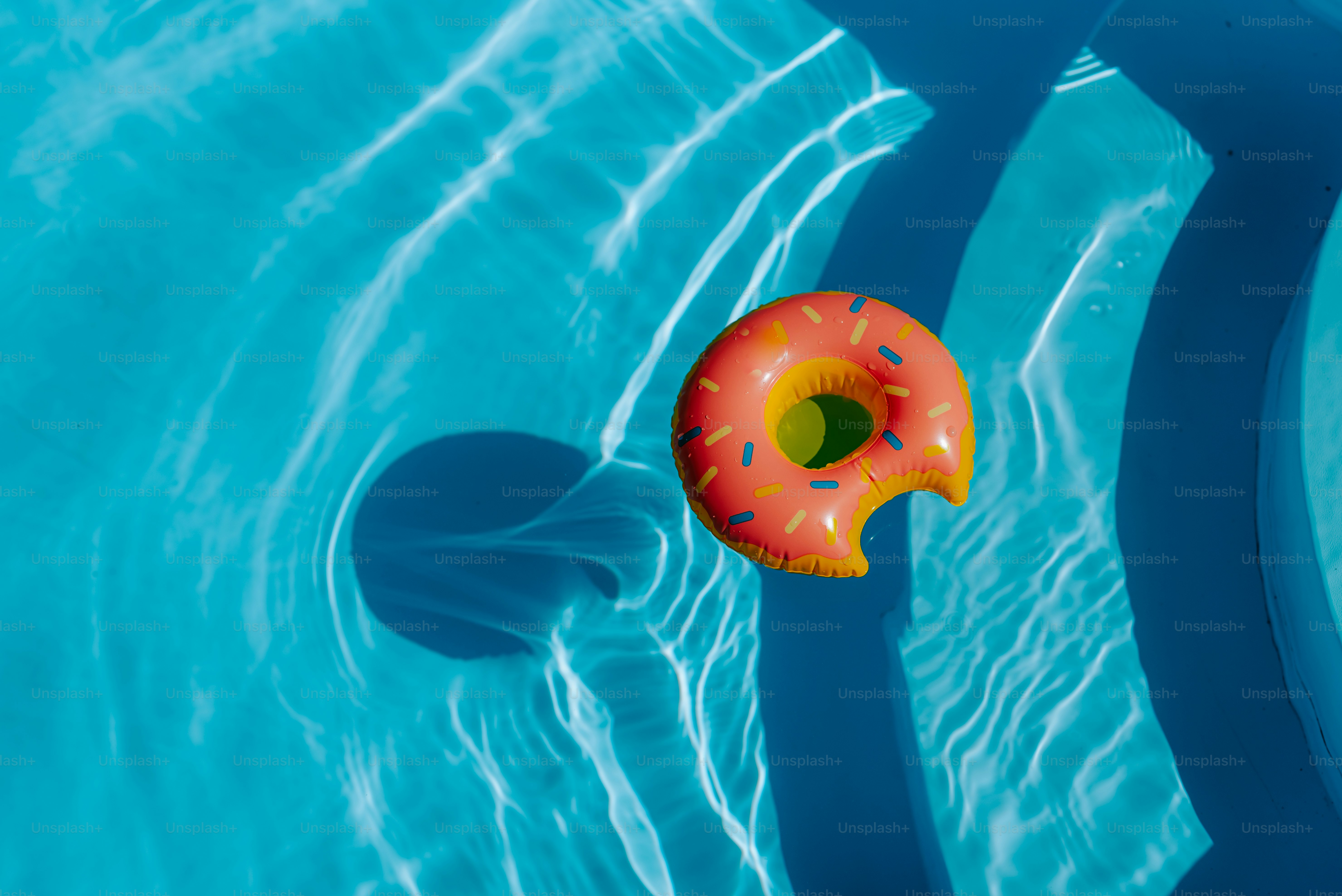 An inflatable donut floating in a pool of water photo – Float Image on ...