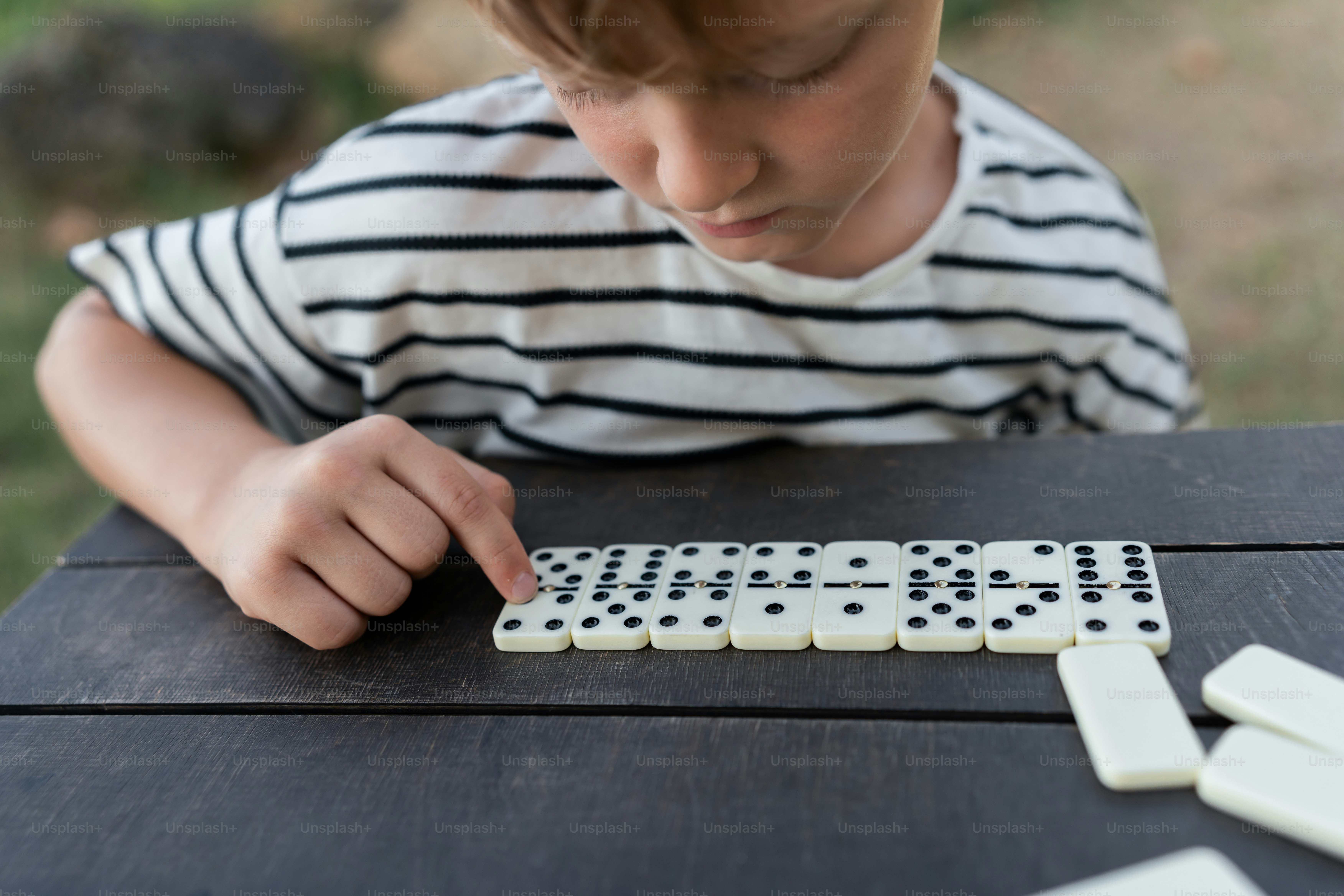 A young boy is playing with dominos on a table photo – Kids Image on ...