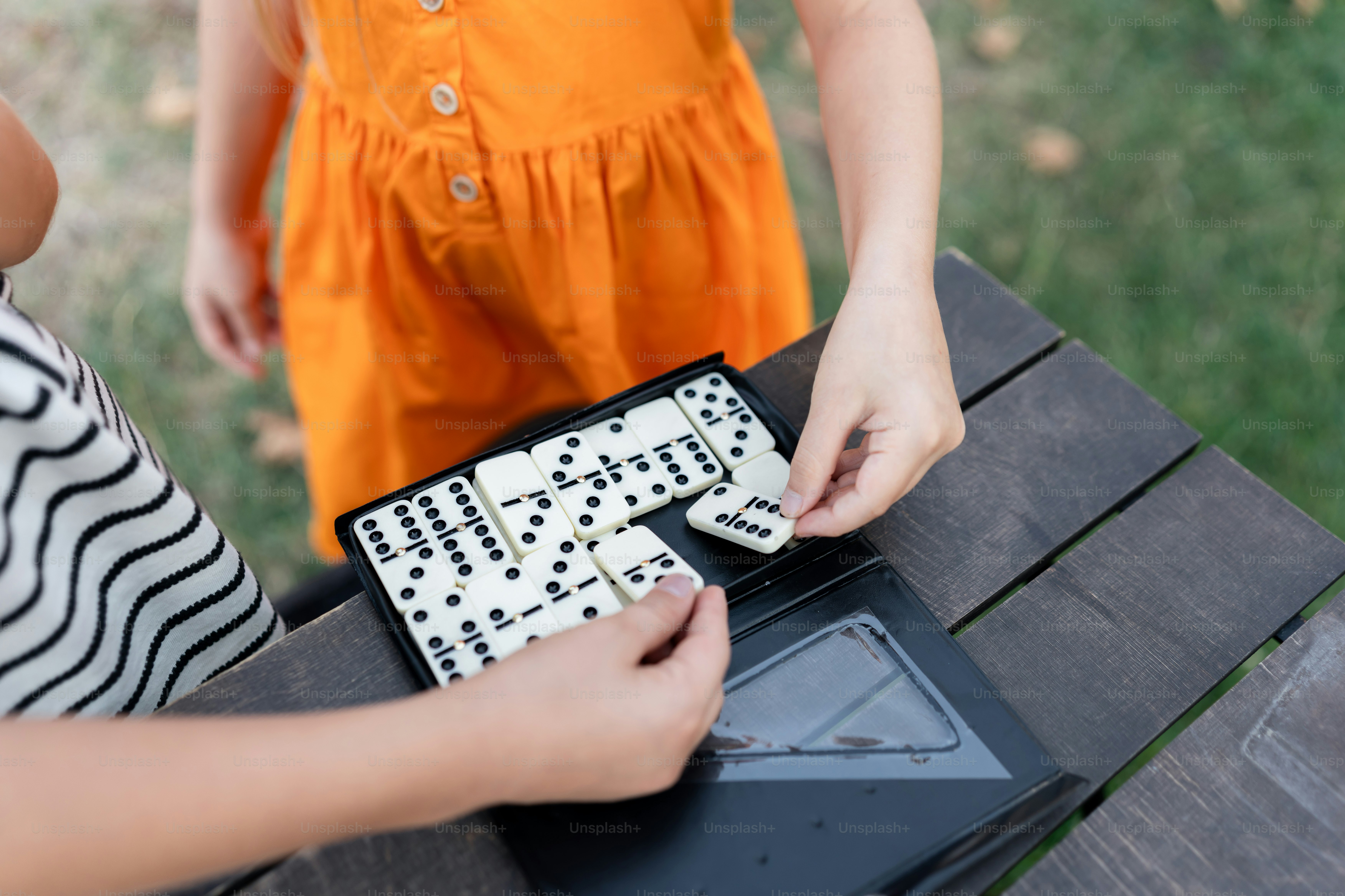 A couple of kids playing a game of dominos photo – Table games Image on ...