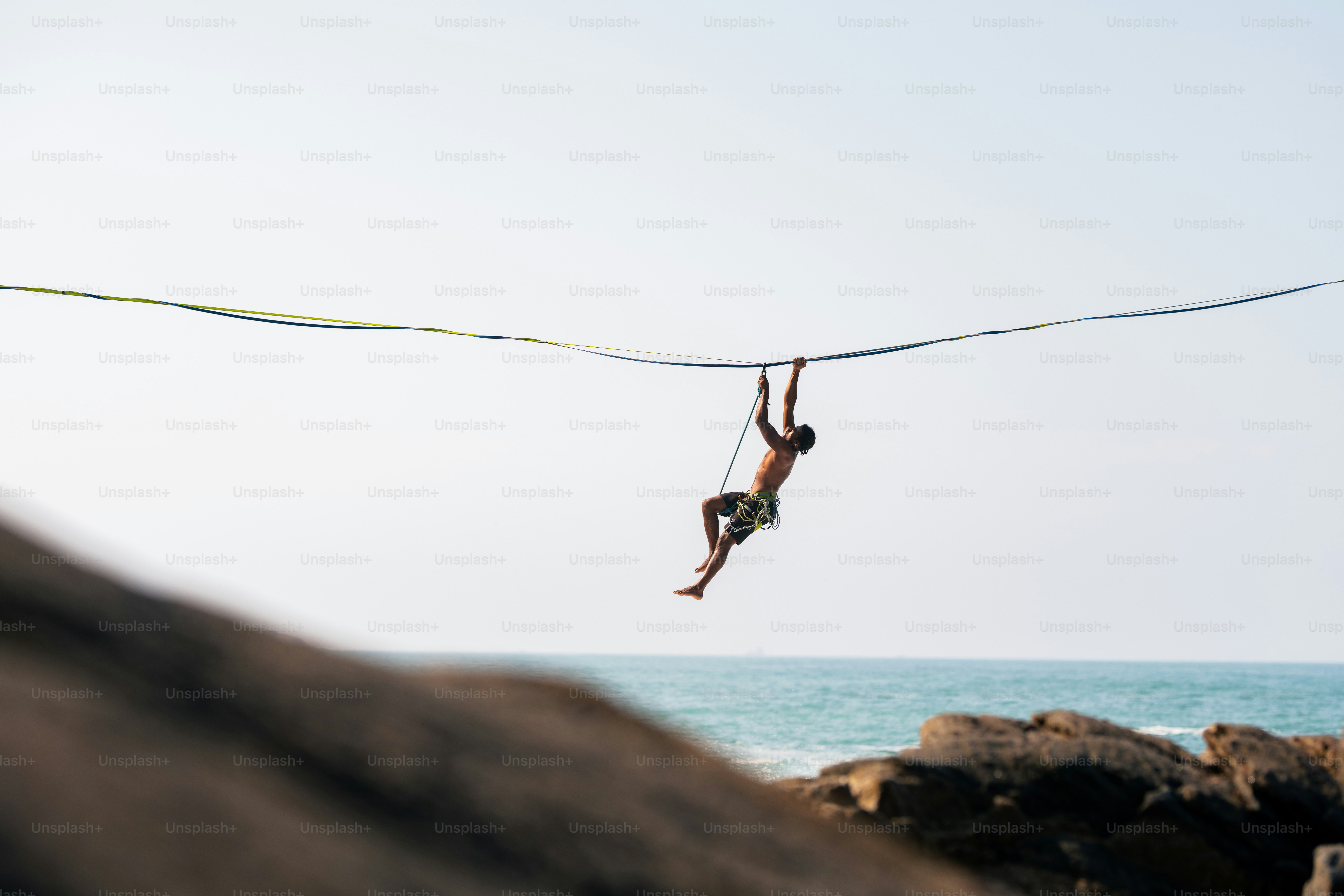A man hanging from a rope over a body of water photo – Agility Image on ...