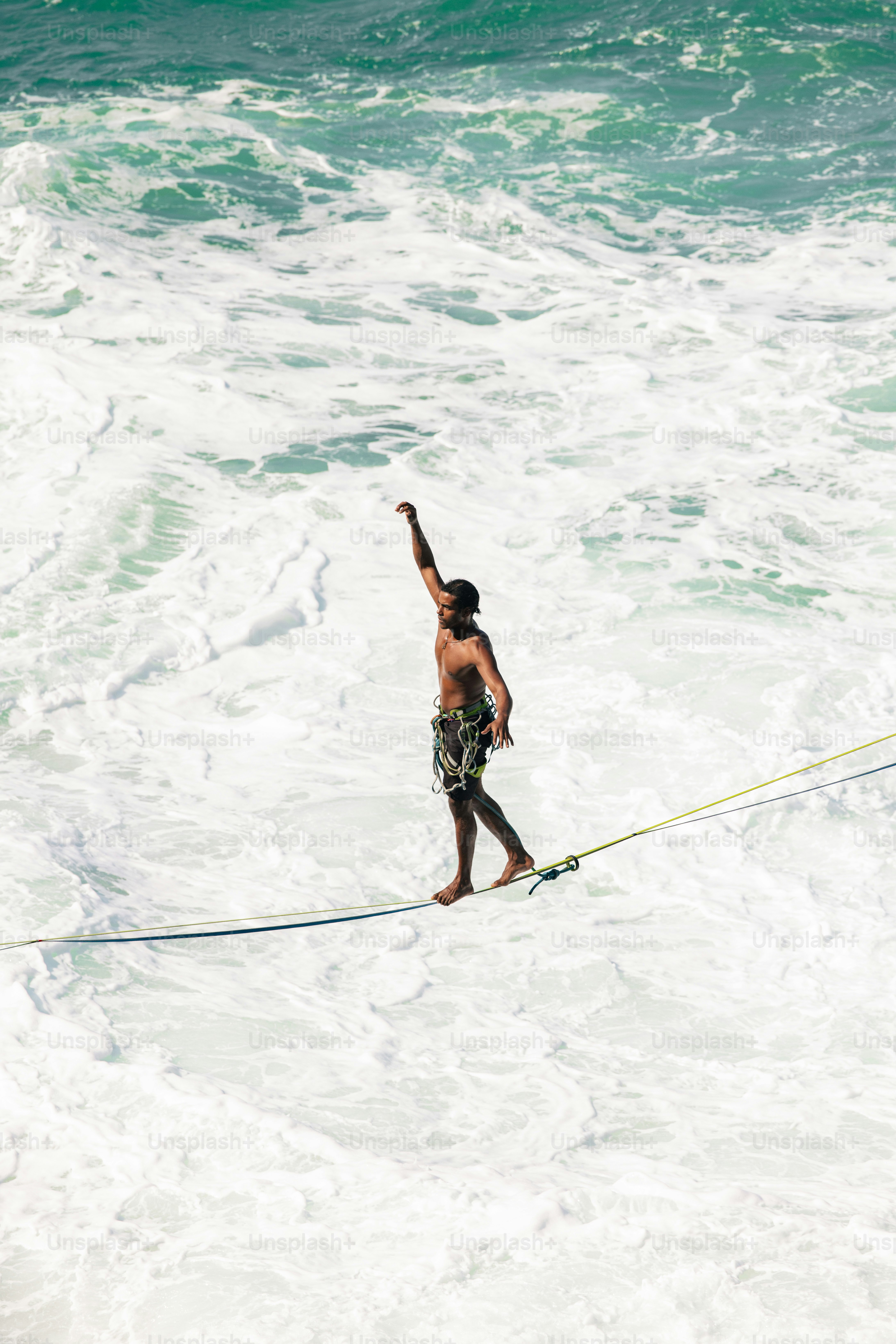 A man walking across a rope in the ocean photo – Outdoor Image on Unsplash