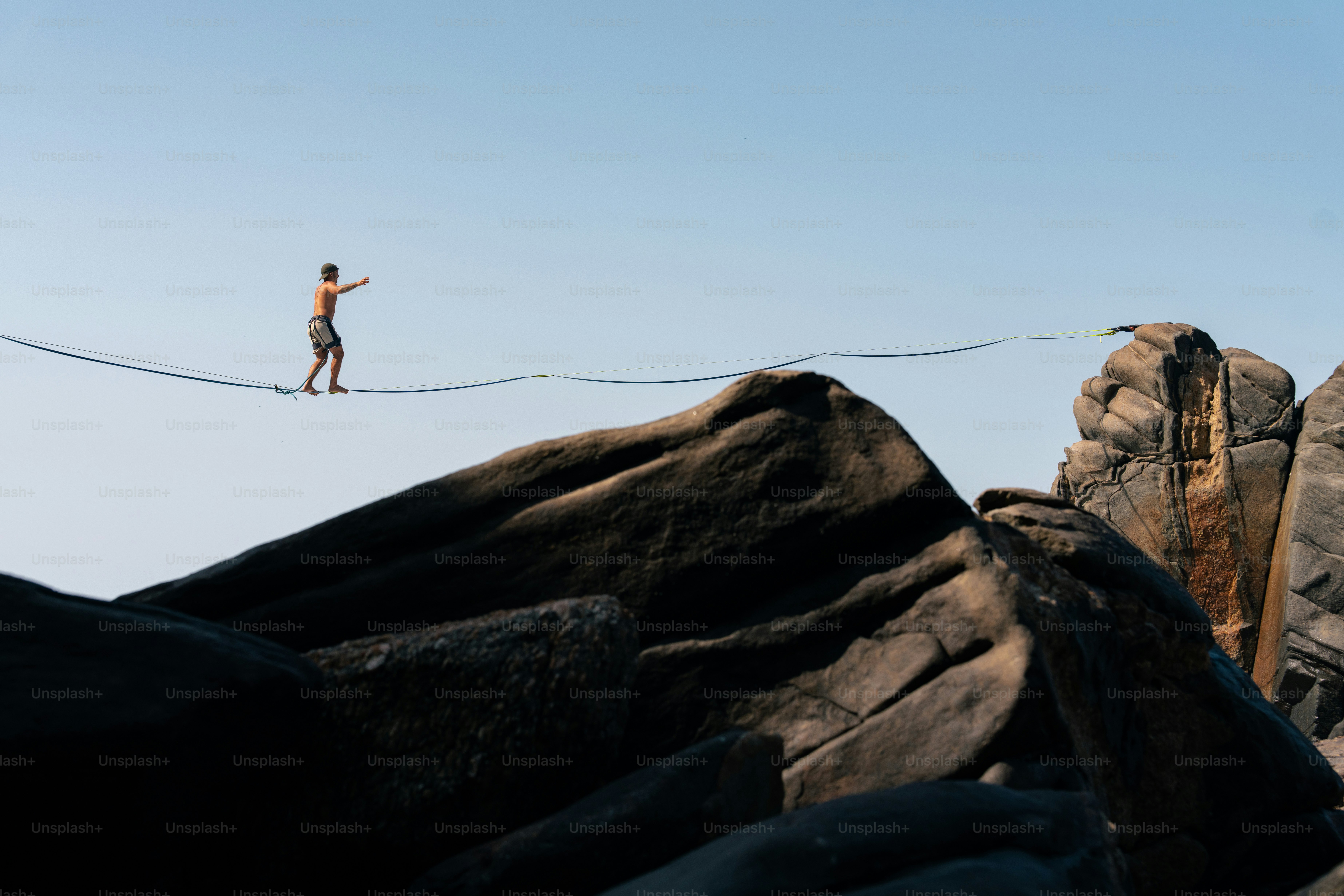 A man walking across a rope over rocks photo – Daring Image on Unsplash