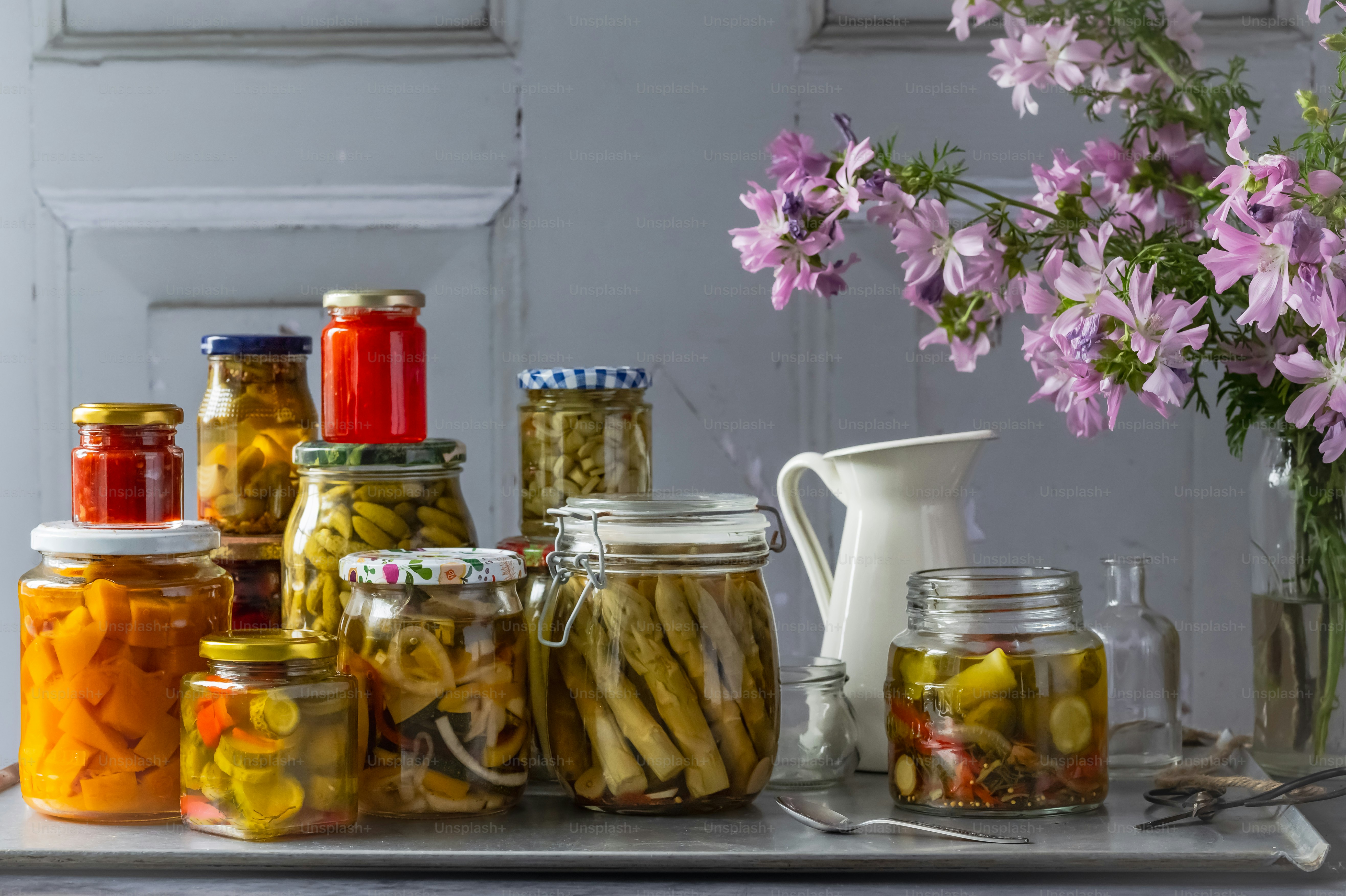 A table topped with jars of pickles and flowers photo – Food in jars ...