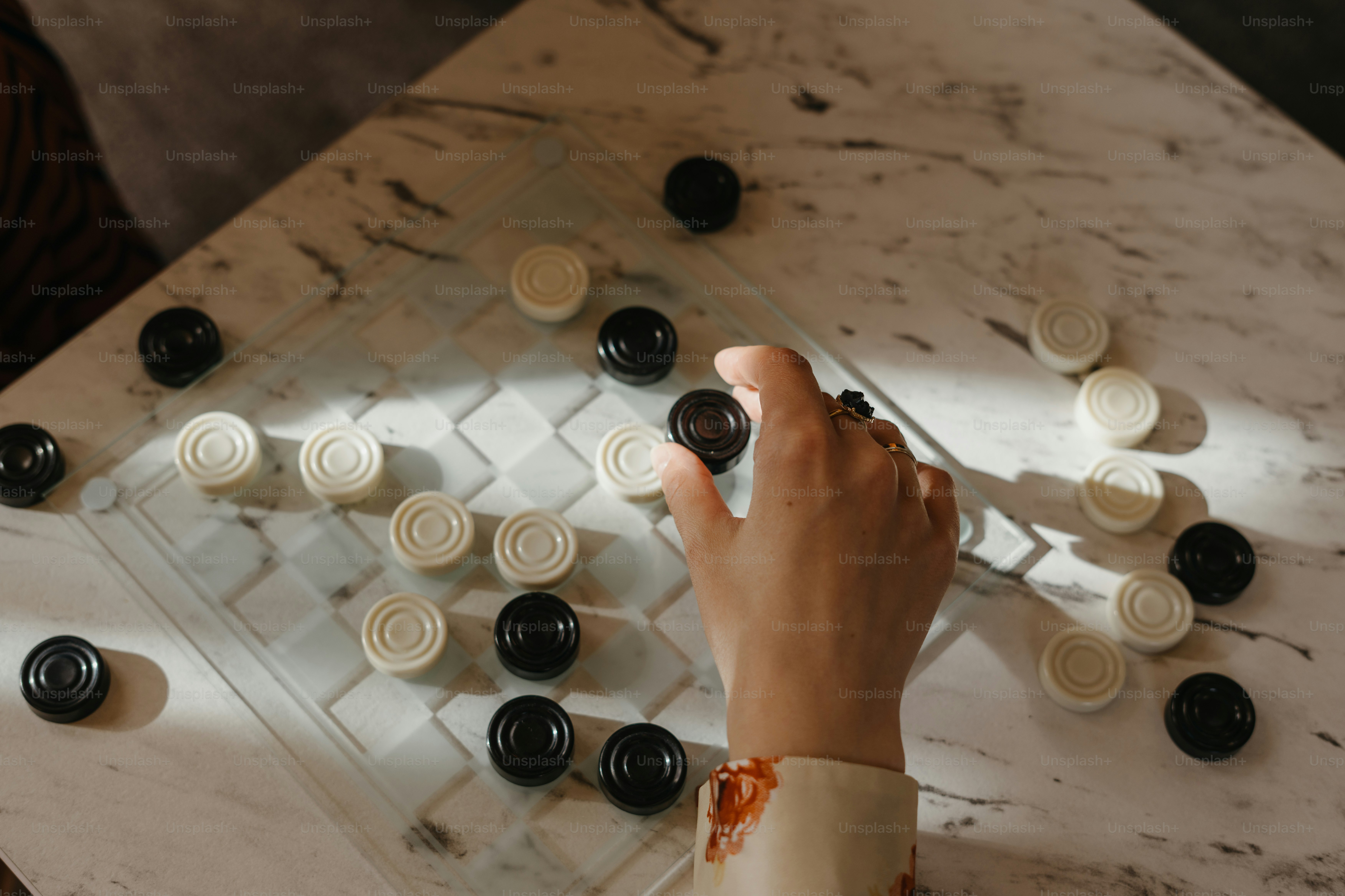 A person playing a game of checkers on a table photo – Game Image on ...