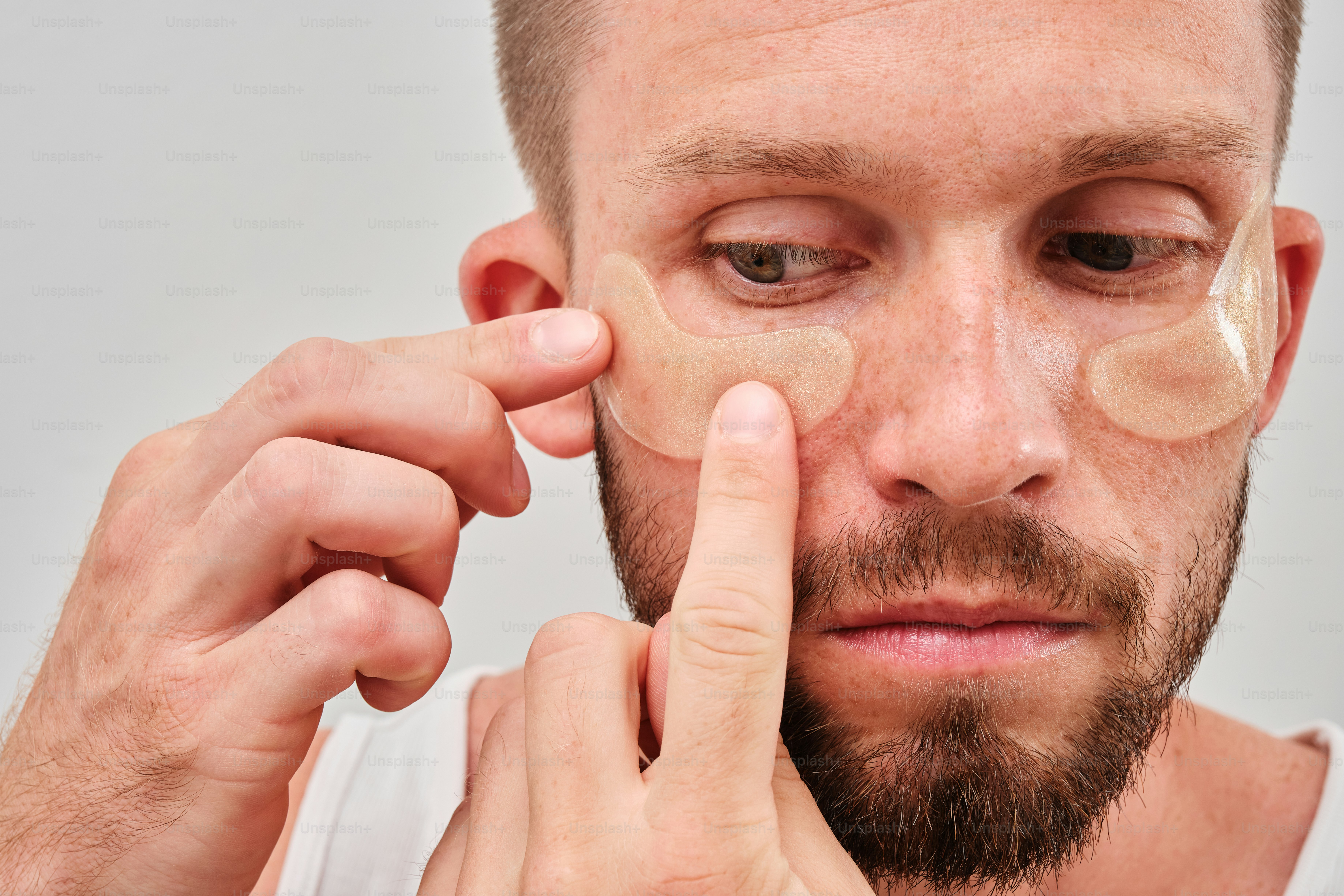 A man holding his eye patch to his face photo – Eye patches Image on ...
