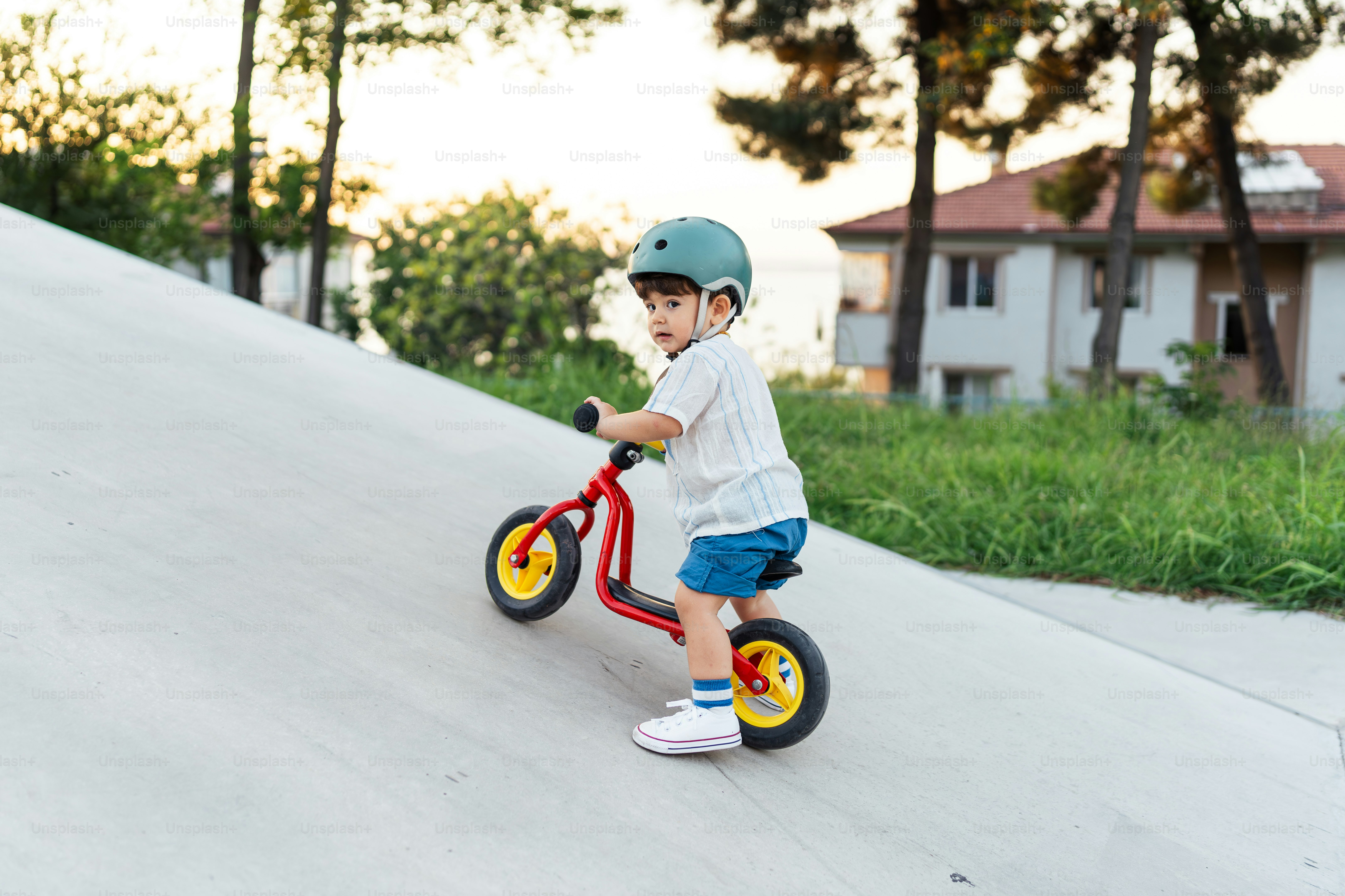 A little boy riding a red bike down a hill photo – Family activities ...