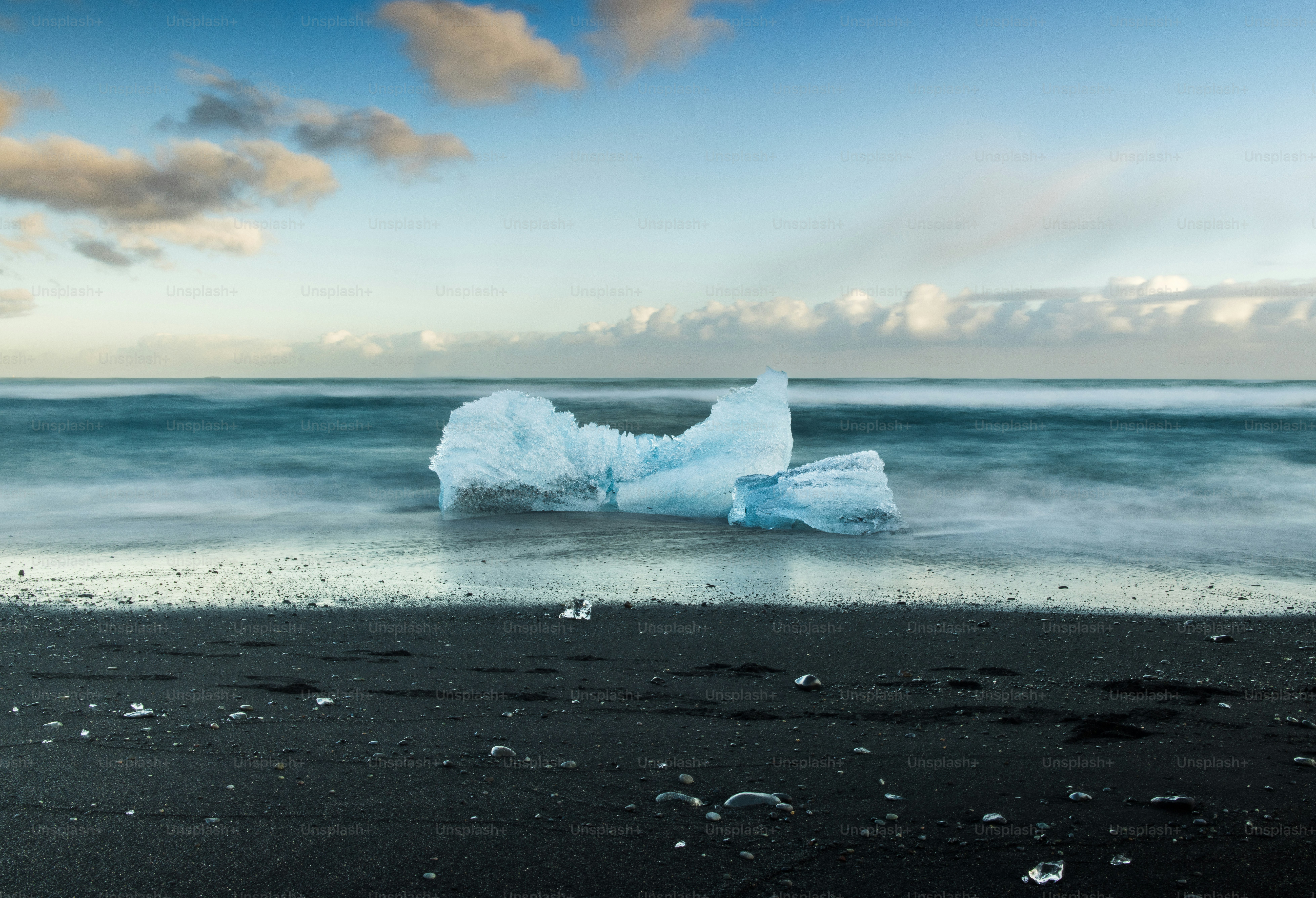 A large iceberg floating on top of a sandy beach photo – Iceland Image ...
