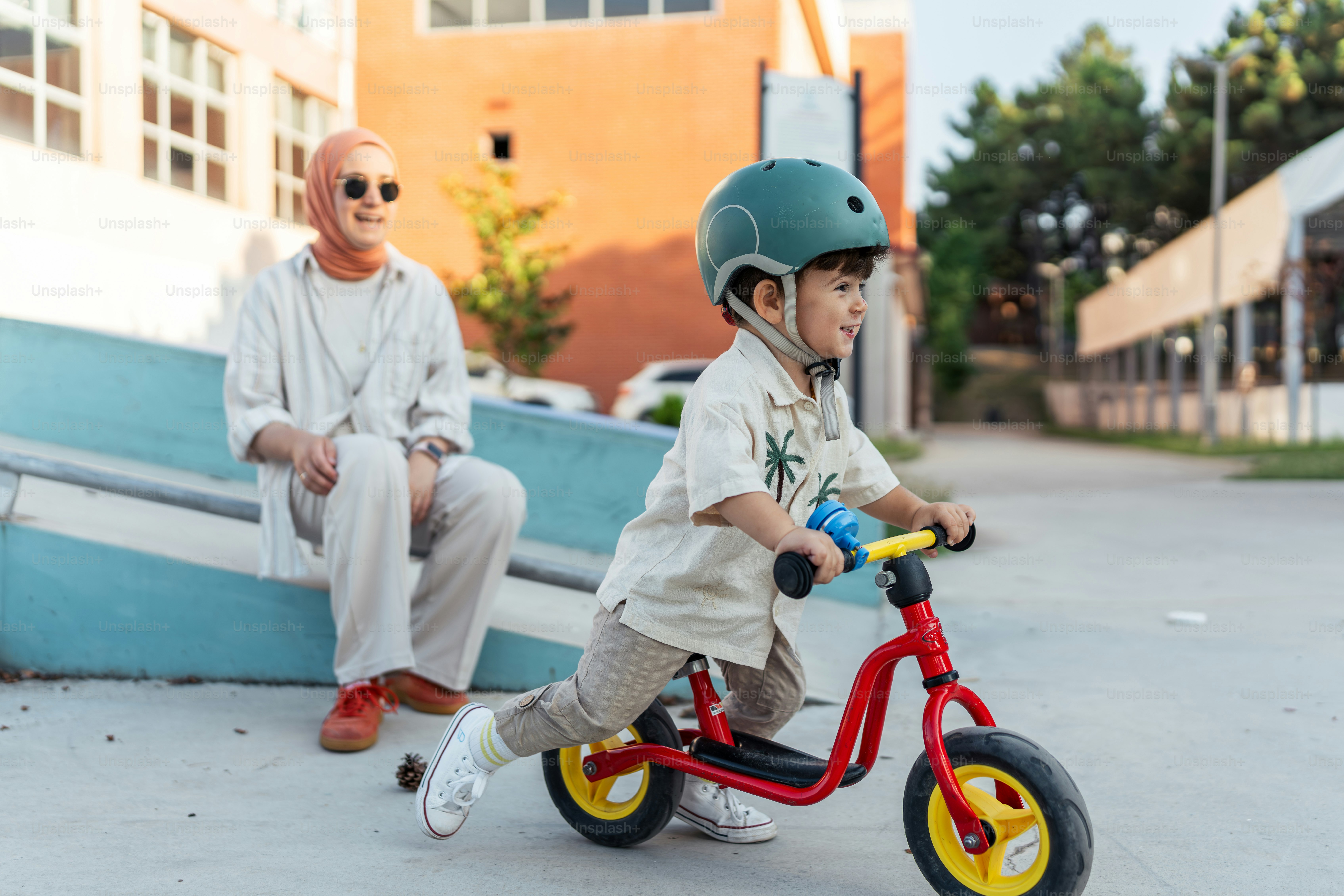A young boy riding a red bike next to an older man photo – Family Image ...