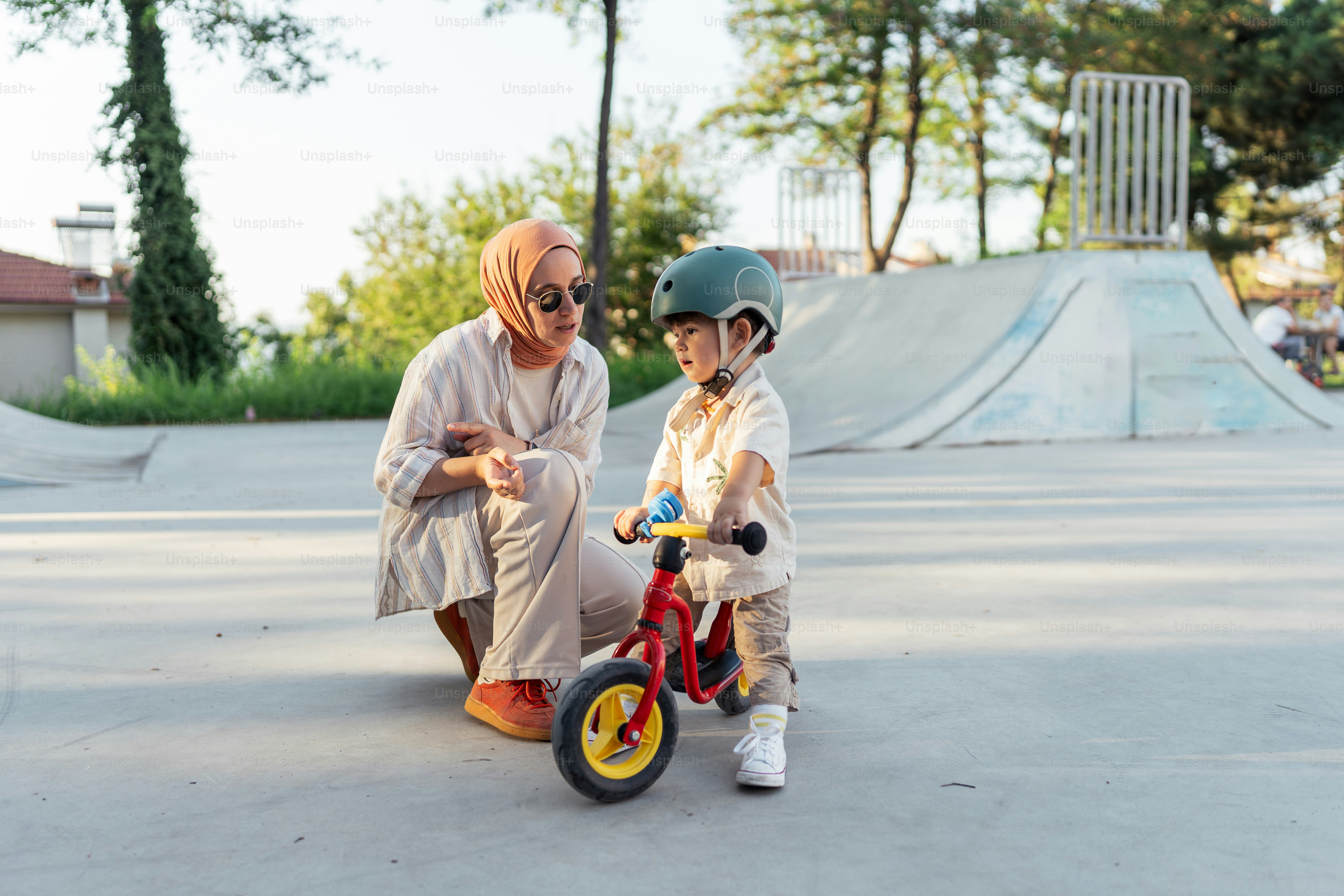 A young boy riding a red bike next to an older man photo – Family Image ...
