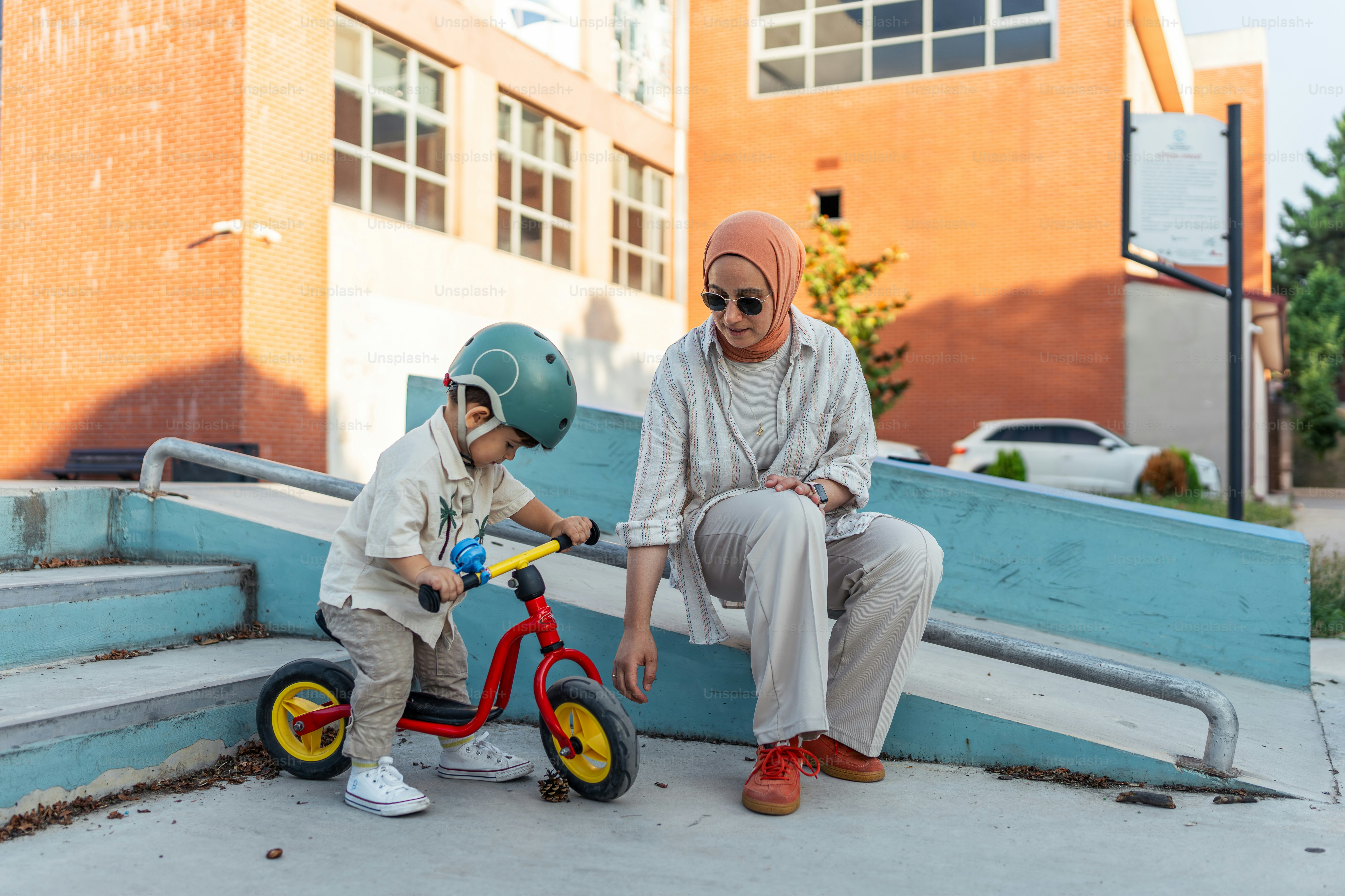 A young boy riding a red bike next to an older man photo – Family Image ...