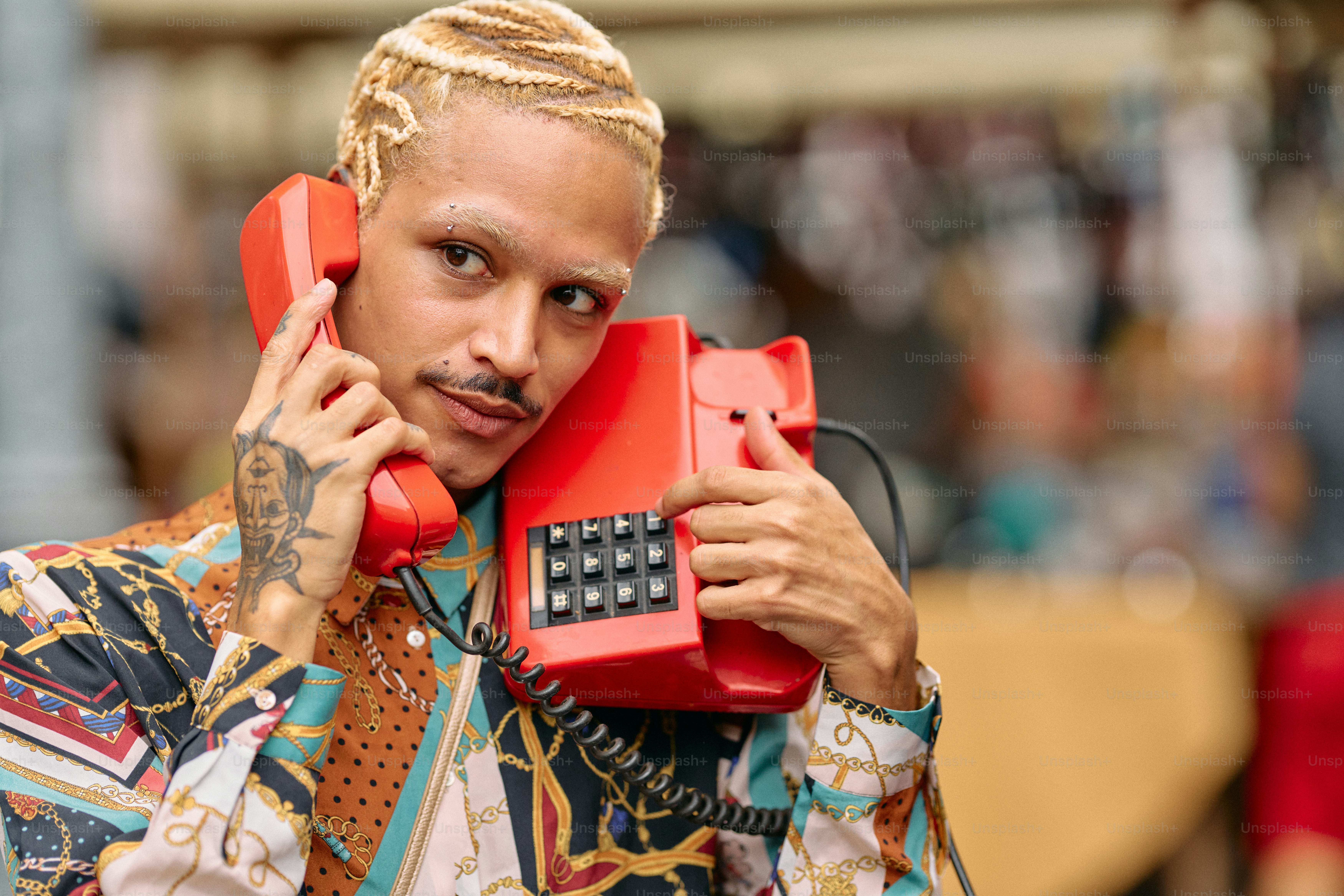 A man holding two red phones up to his face photo – Portrait Image on ...