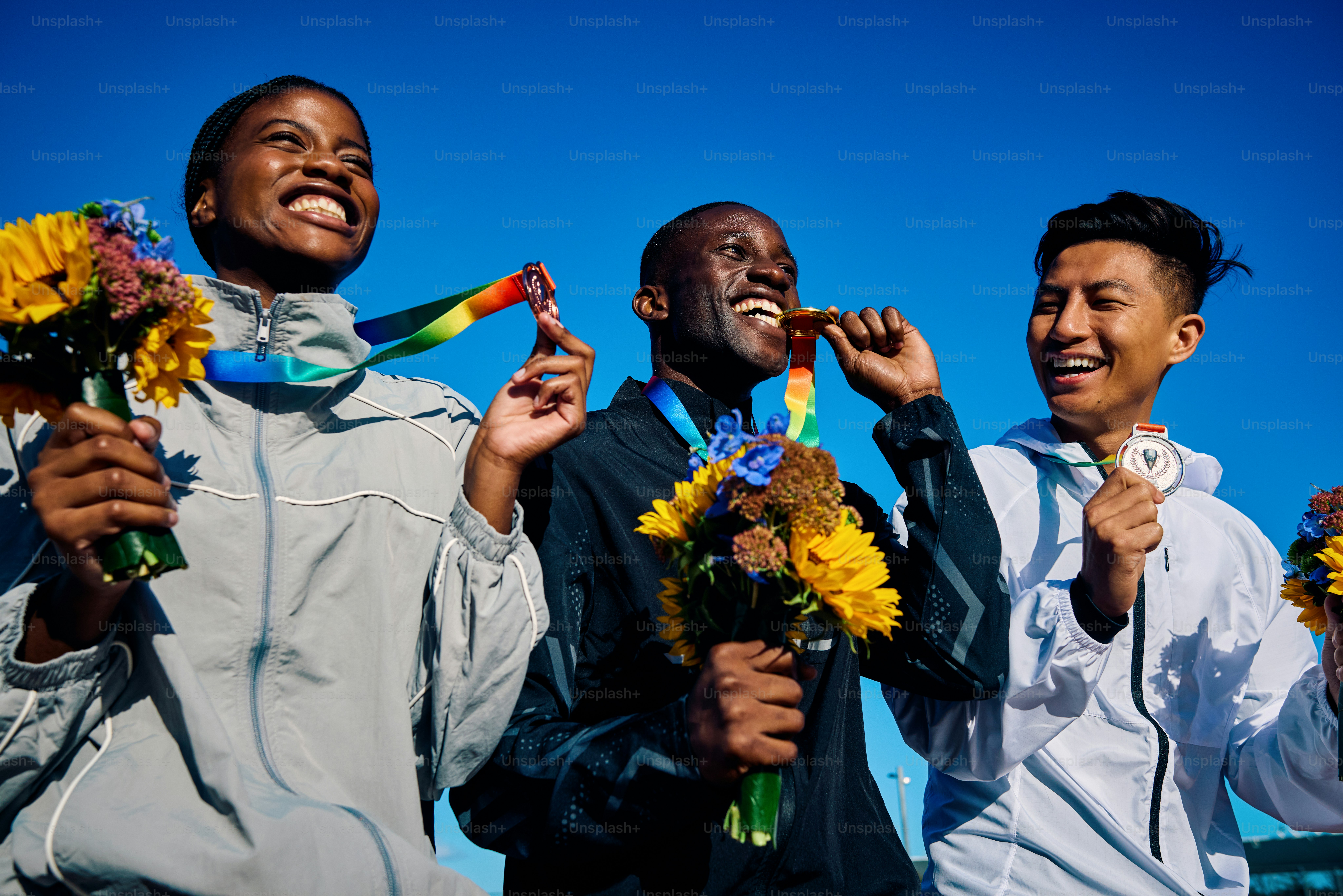Group of Olympic athletes with medals and bouquets celebrating victory ...