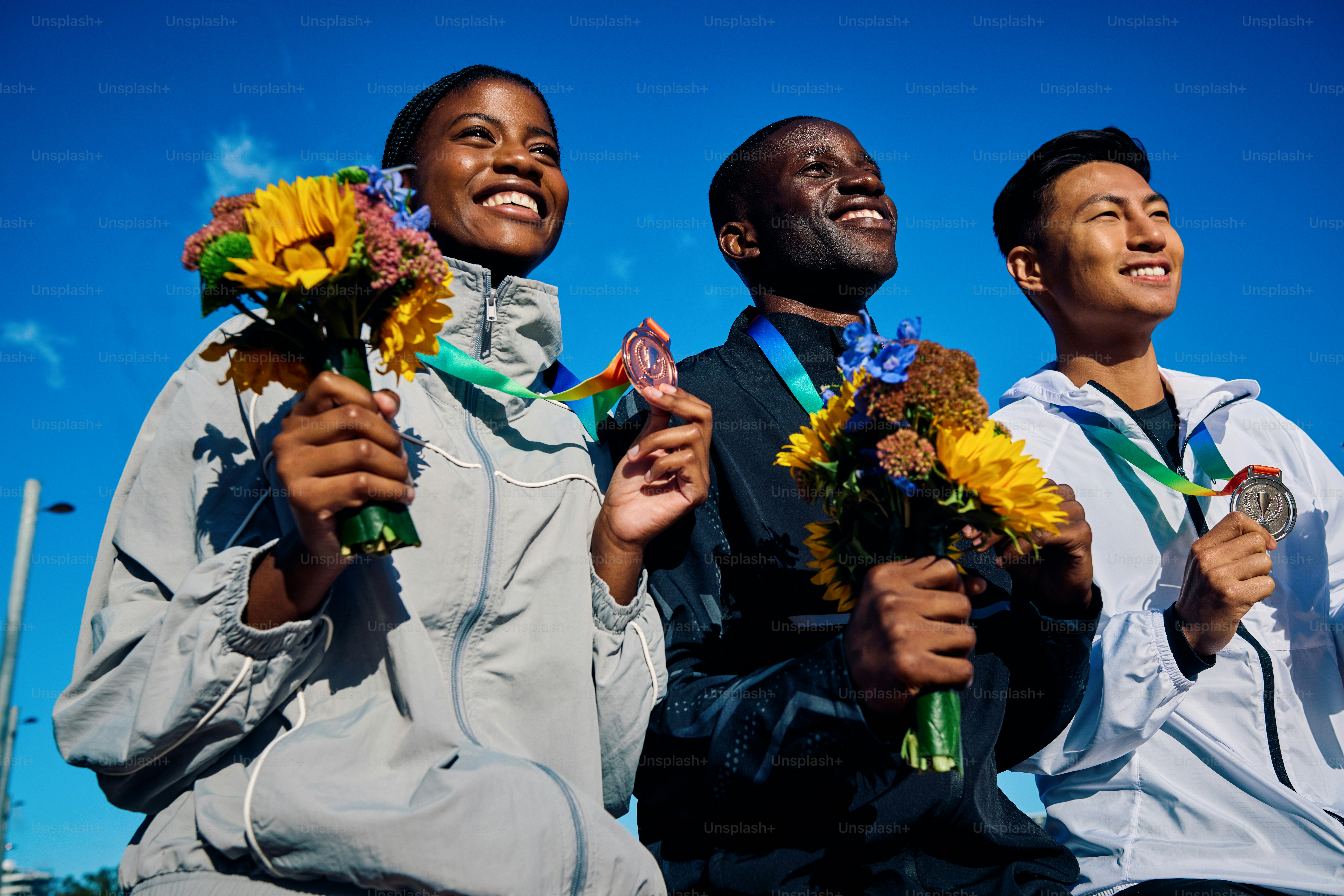 Group of International athletes with medals and bouquets celebrating ...