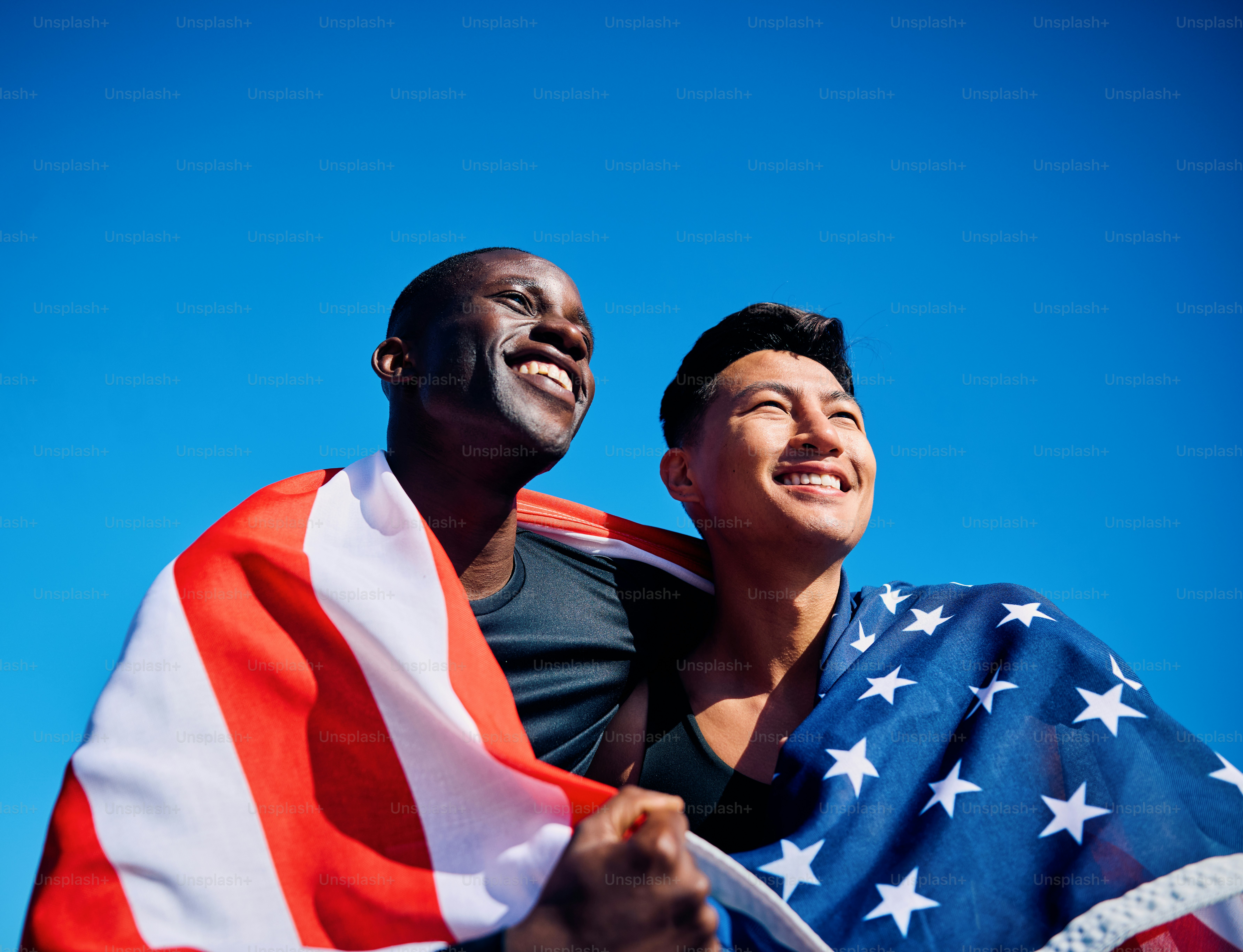 Two International athletes wrapped in American flags looking forward ...