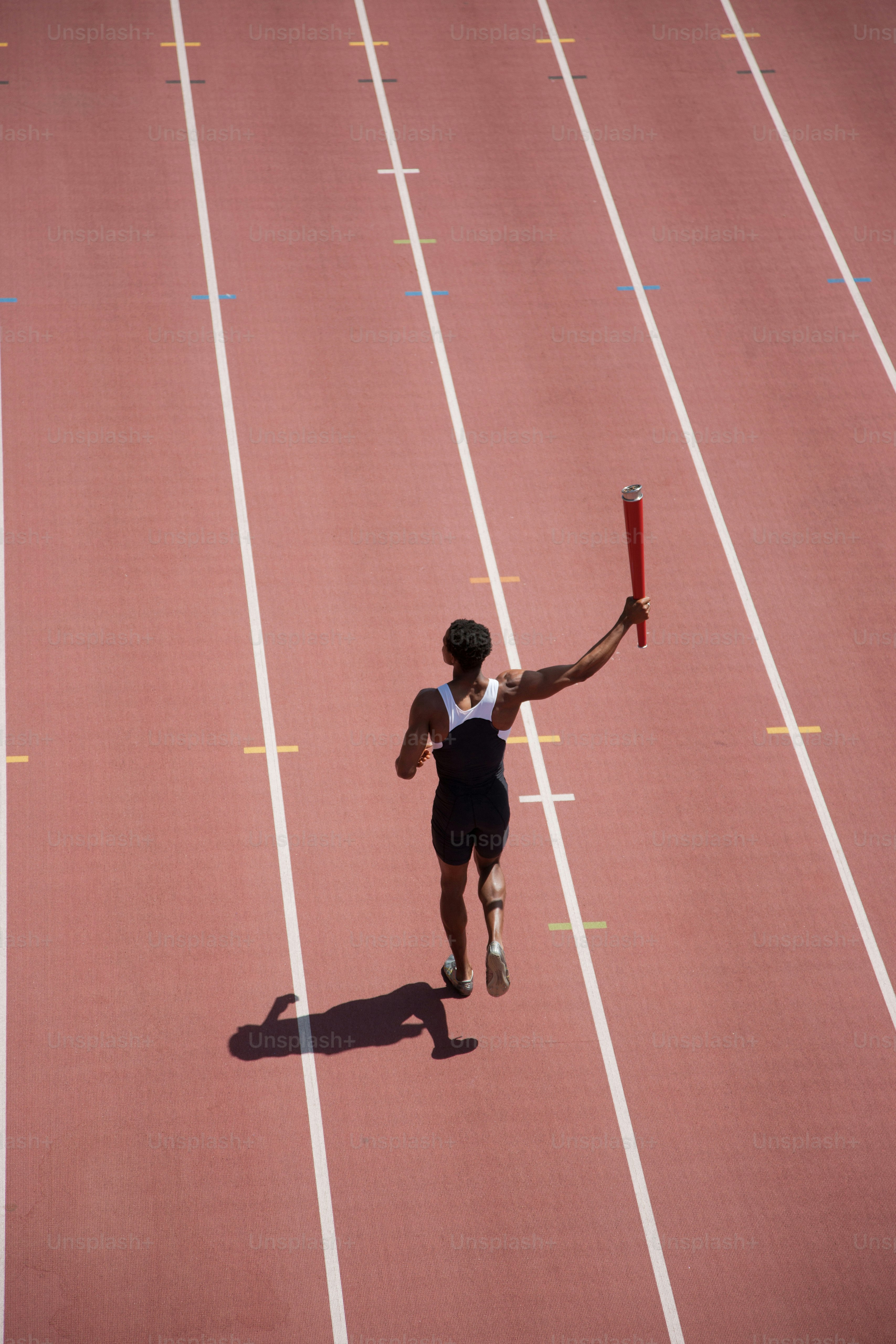A man running on a track with a bat in his hand photo – Tradition Image ...
