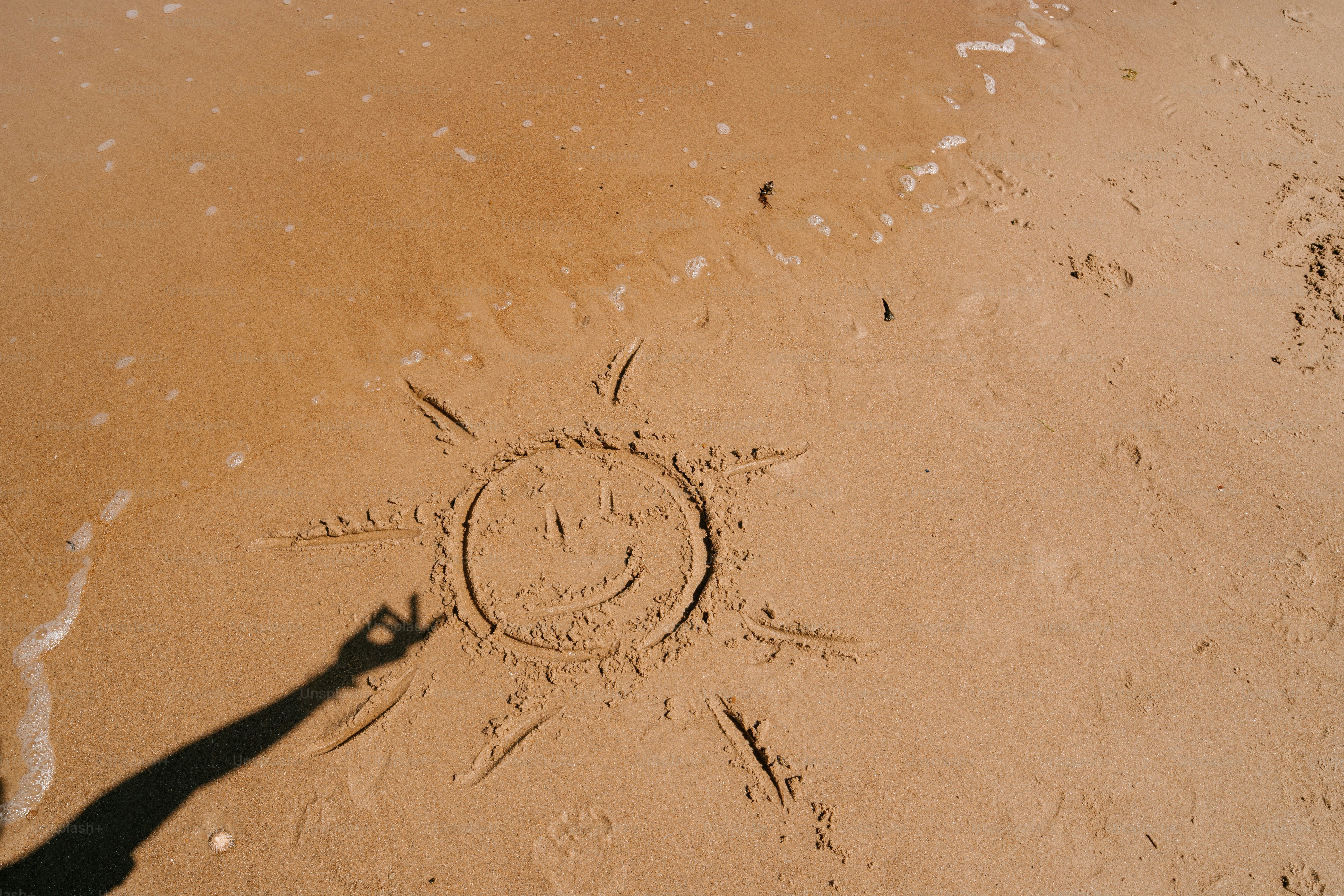 A person standing in the sand with a smiley face drawn in the sand ...