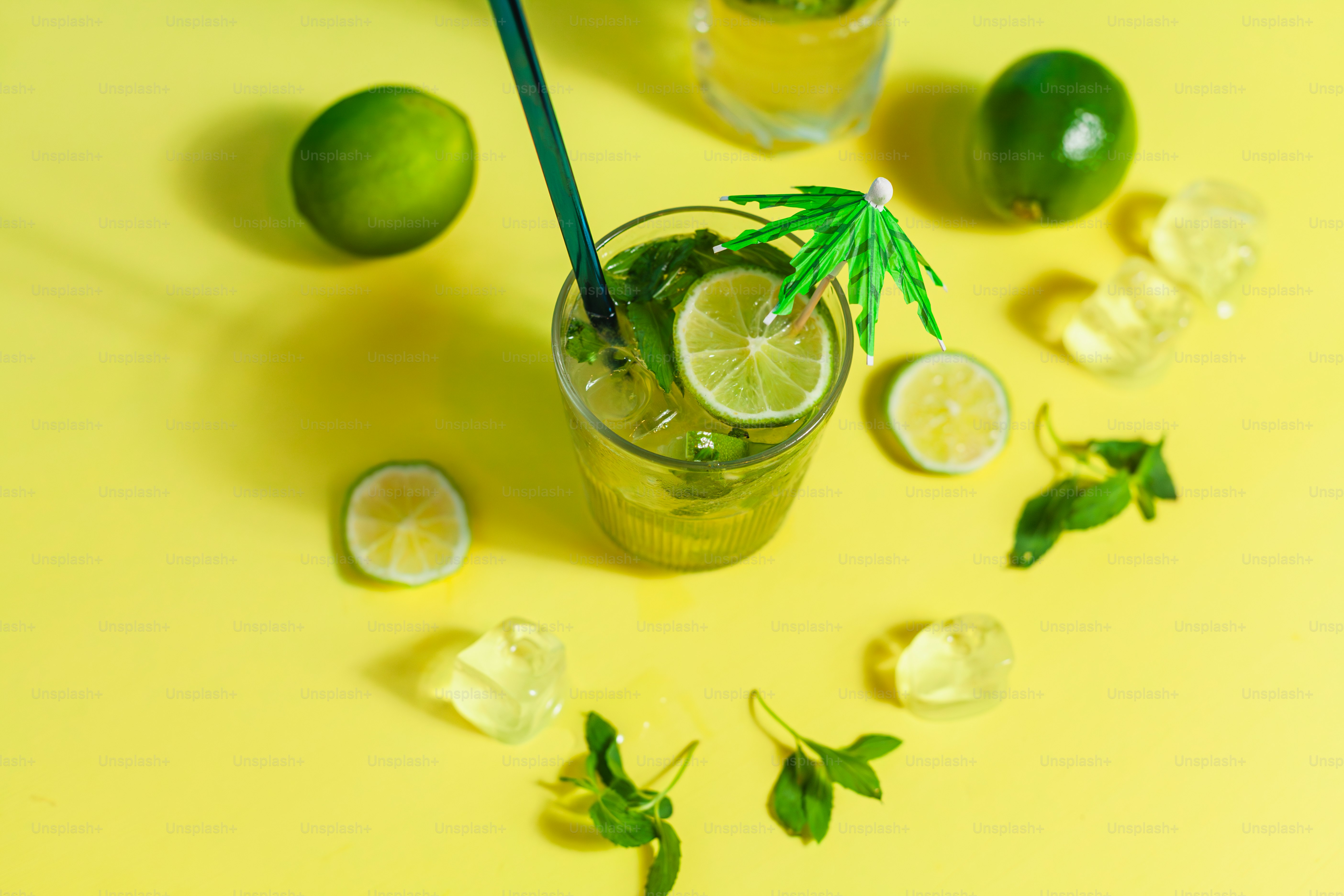 A shot glass with a lime and limeade garnish on a yellow background ...