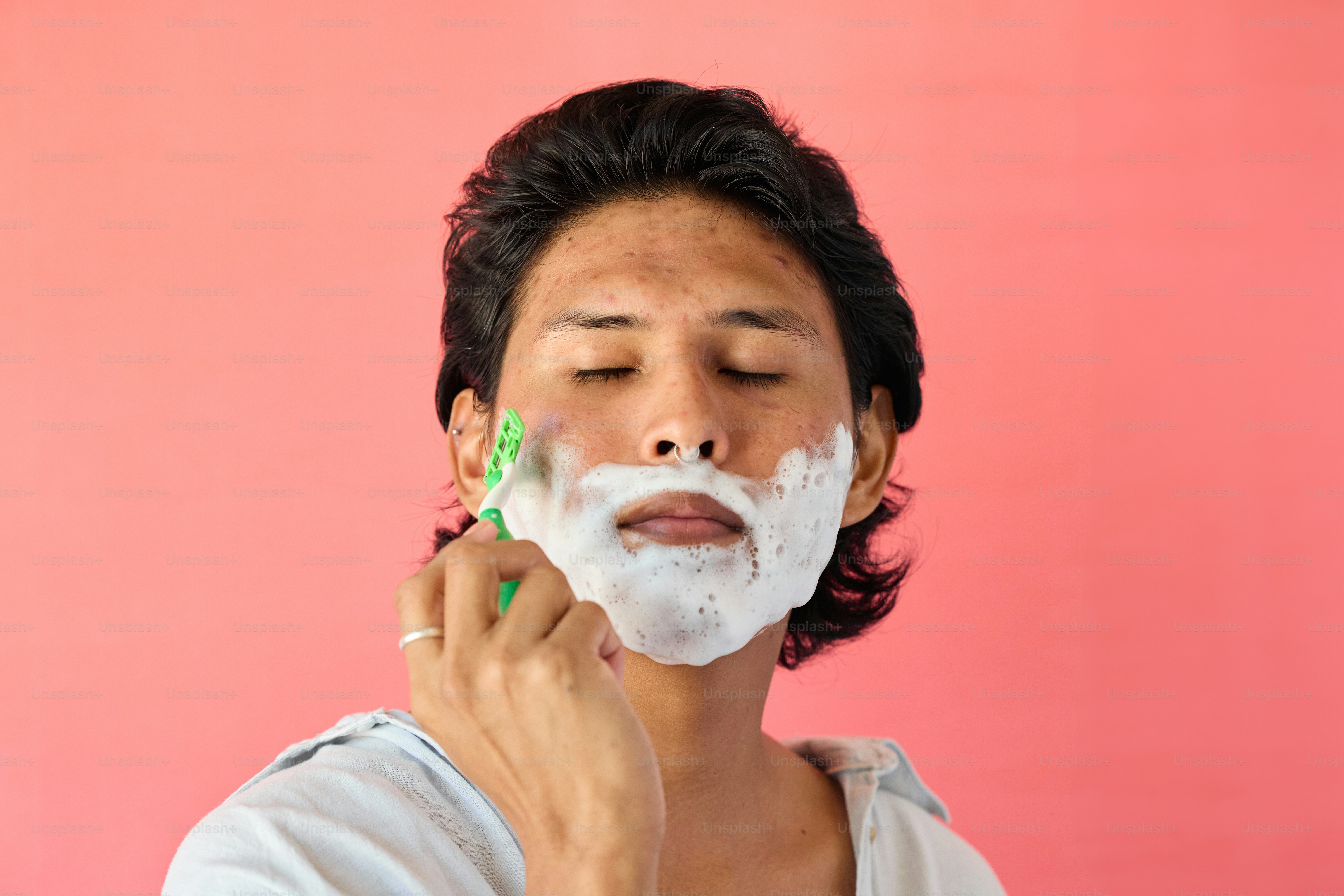 A man shaving his face with a green toothbrush photo – Shaving Image on ...