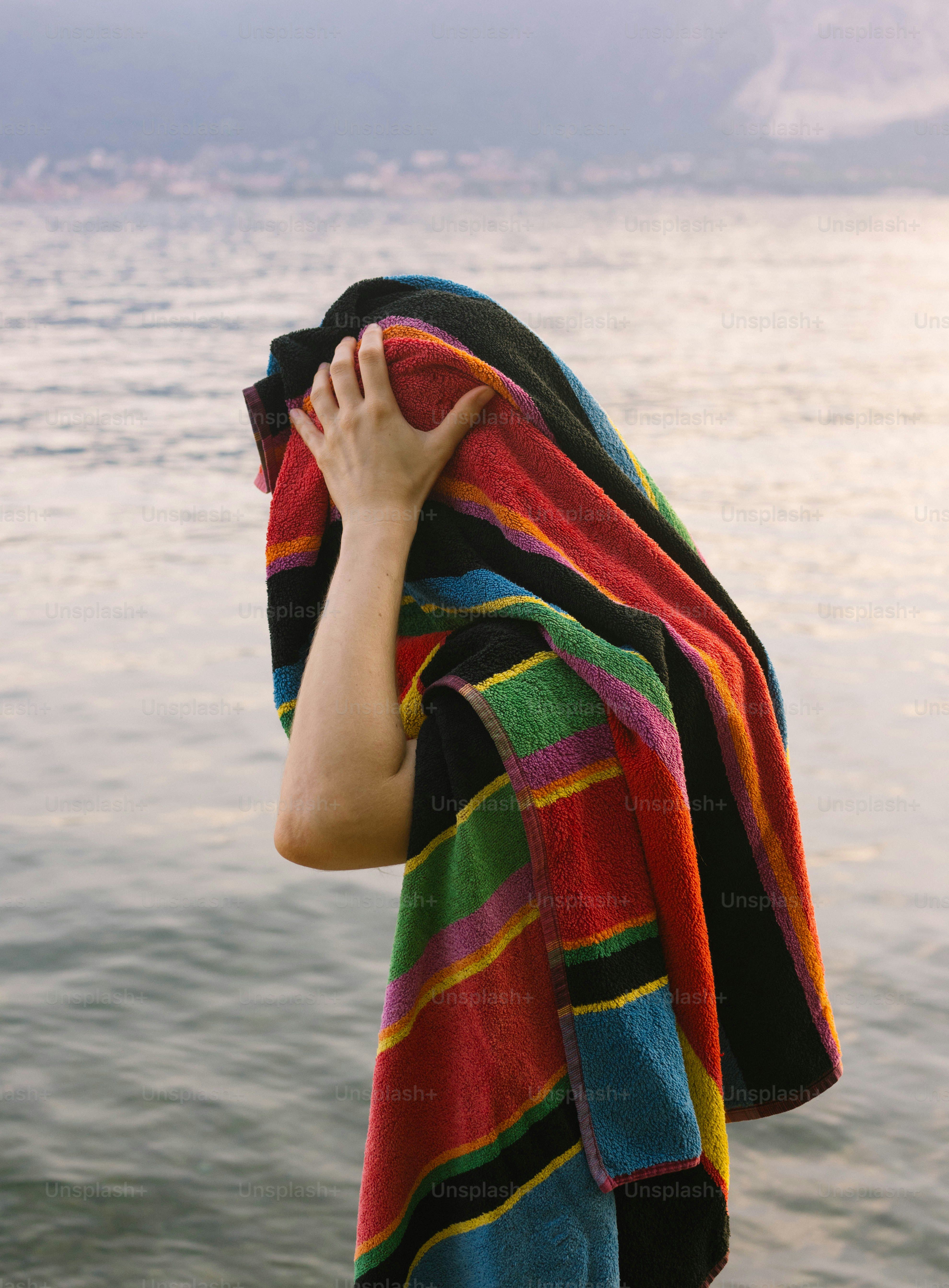 A person standing on a beach with a towel over their head photo – Towel ...