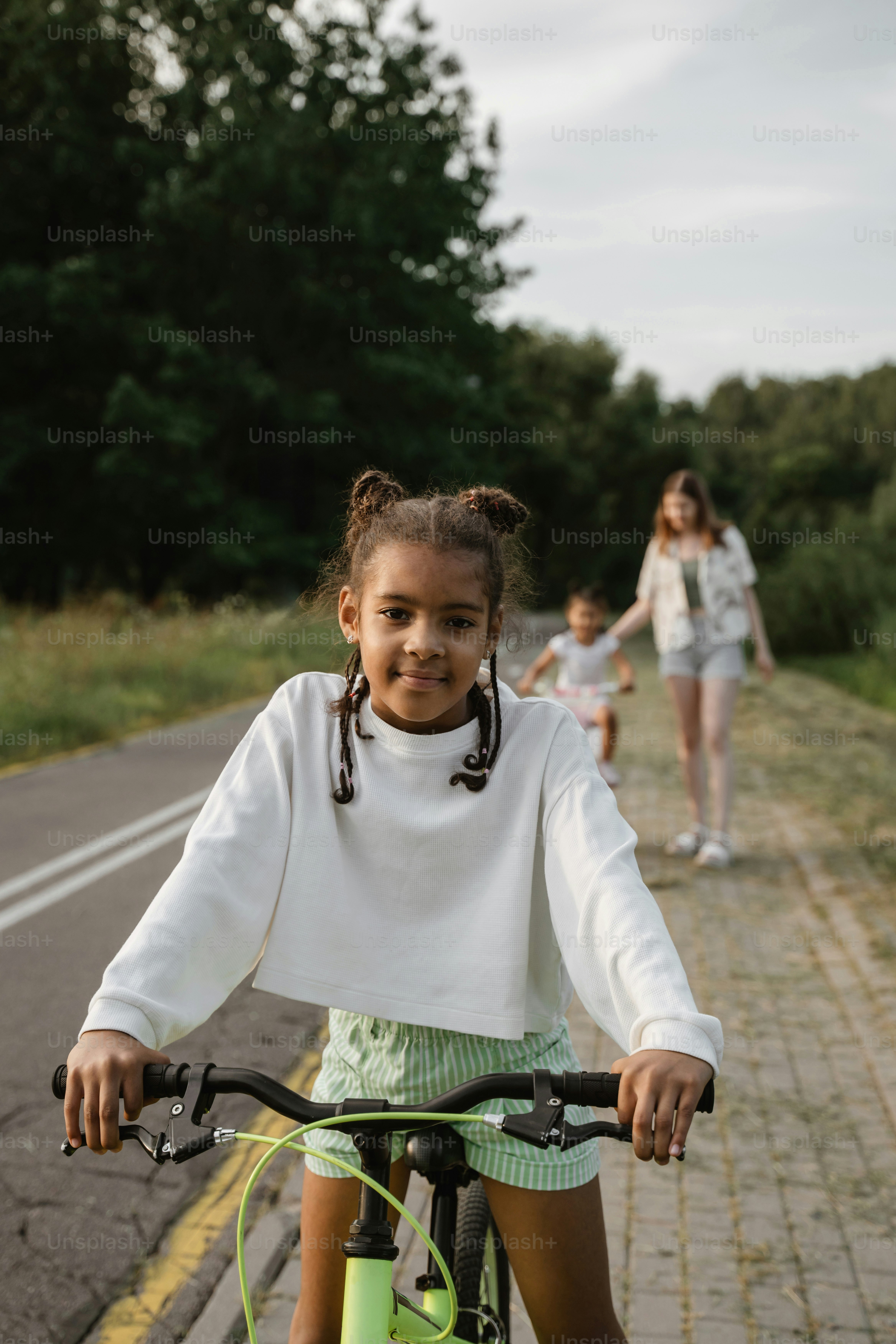A little girl riding a bike down a street photo – Summer activities ...