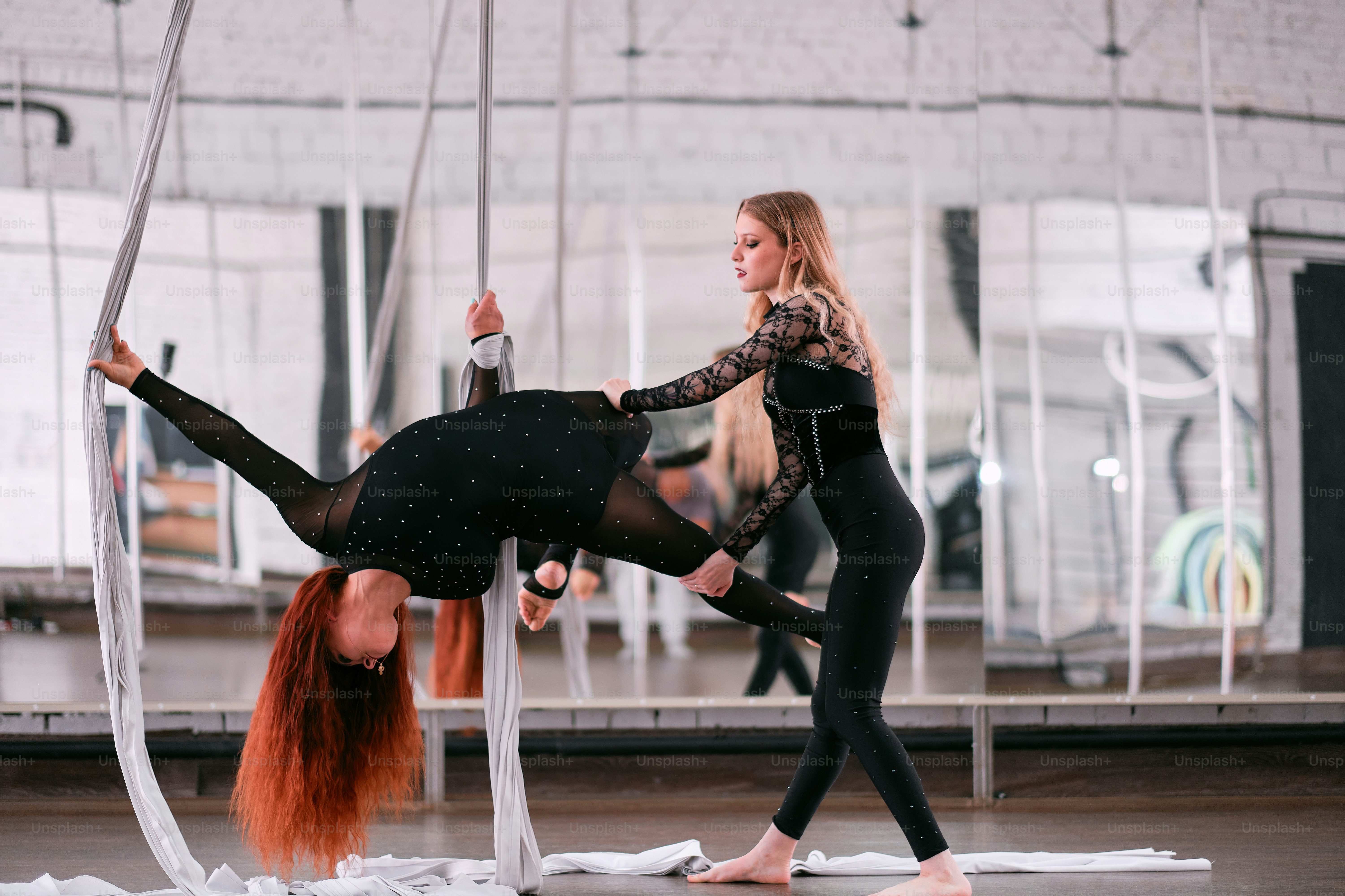 Two women doing acrobatic tricks on a pole photo – Performance Image on ...