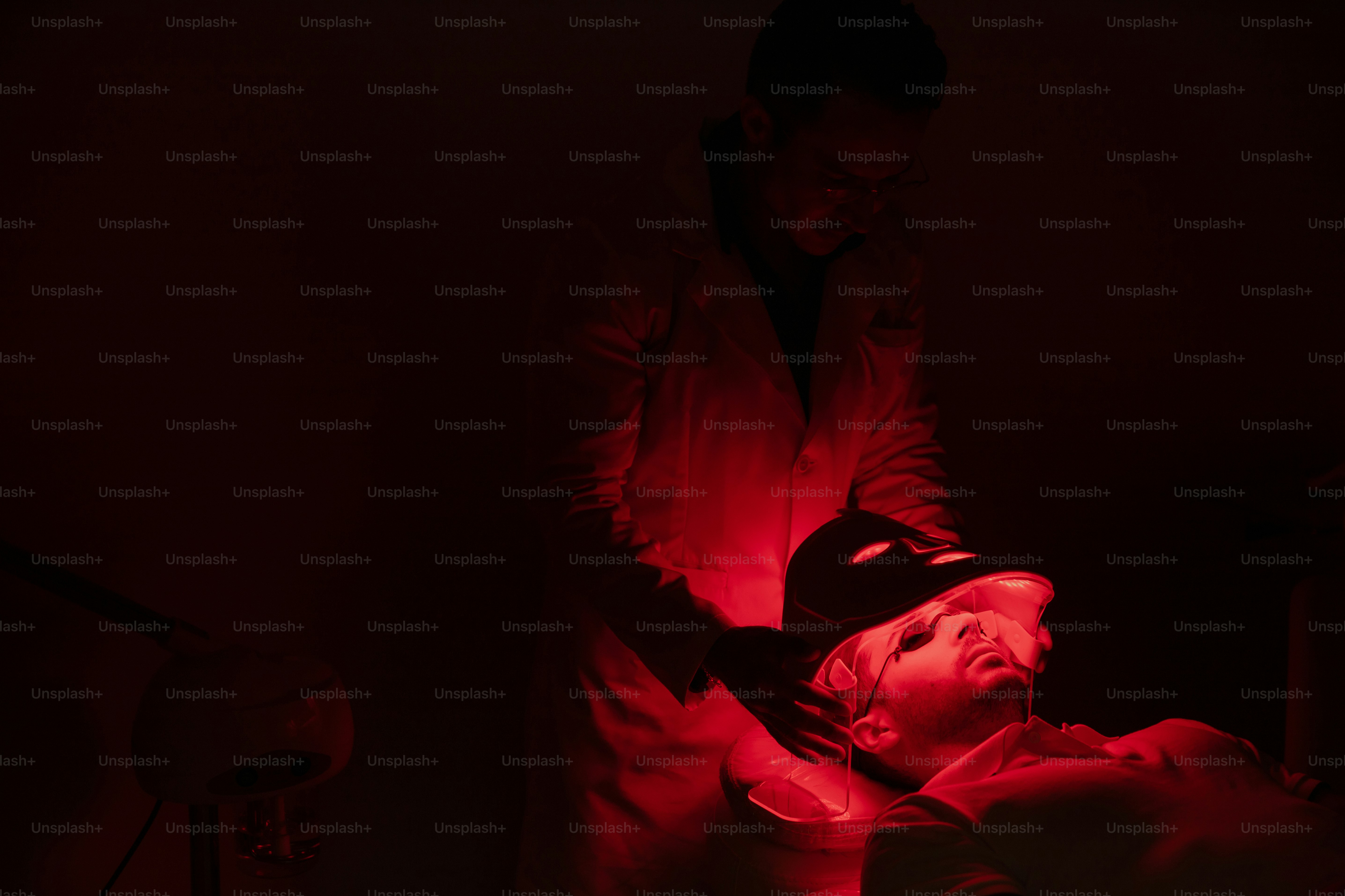 A person laying in a bed with a red light photo – Led face mask Image ...