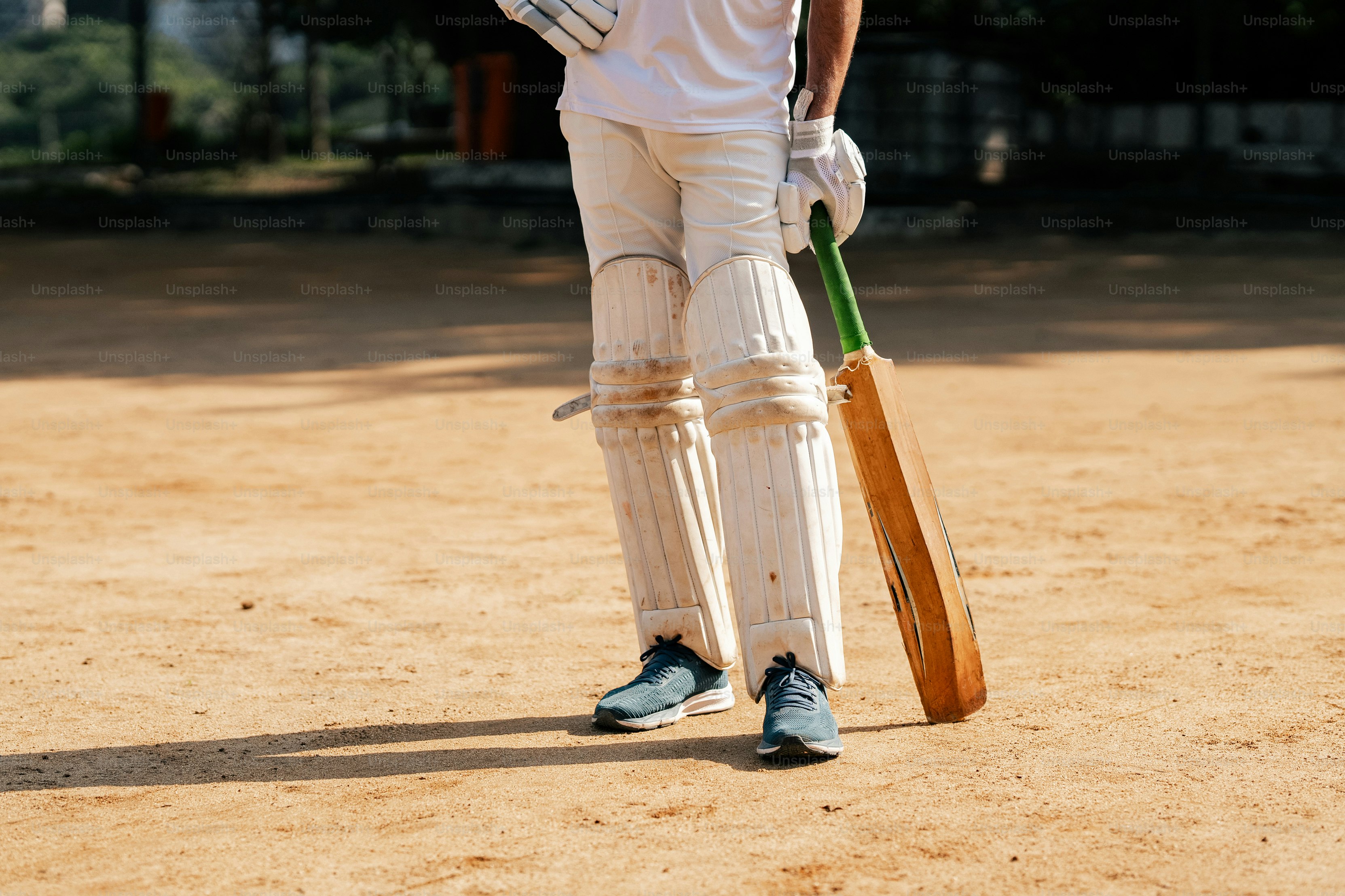A young man holding a cricket bat on a field photo – Cricket Image on ...