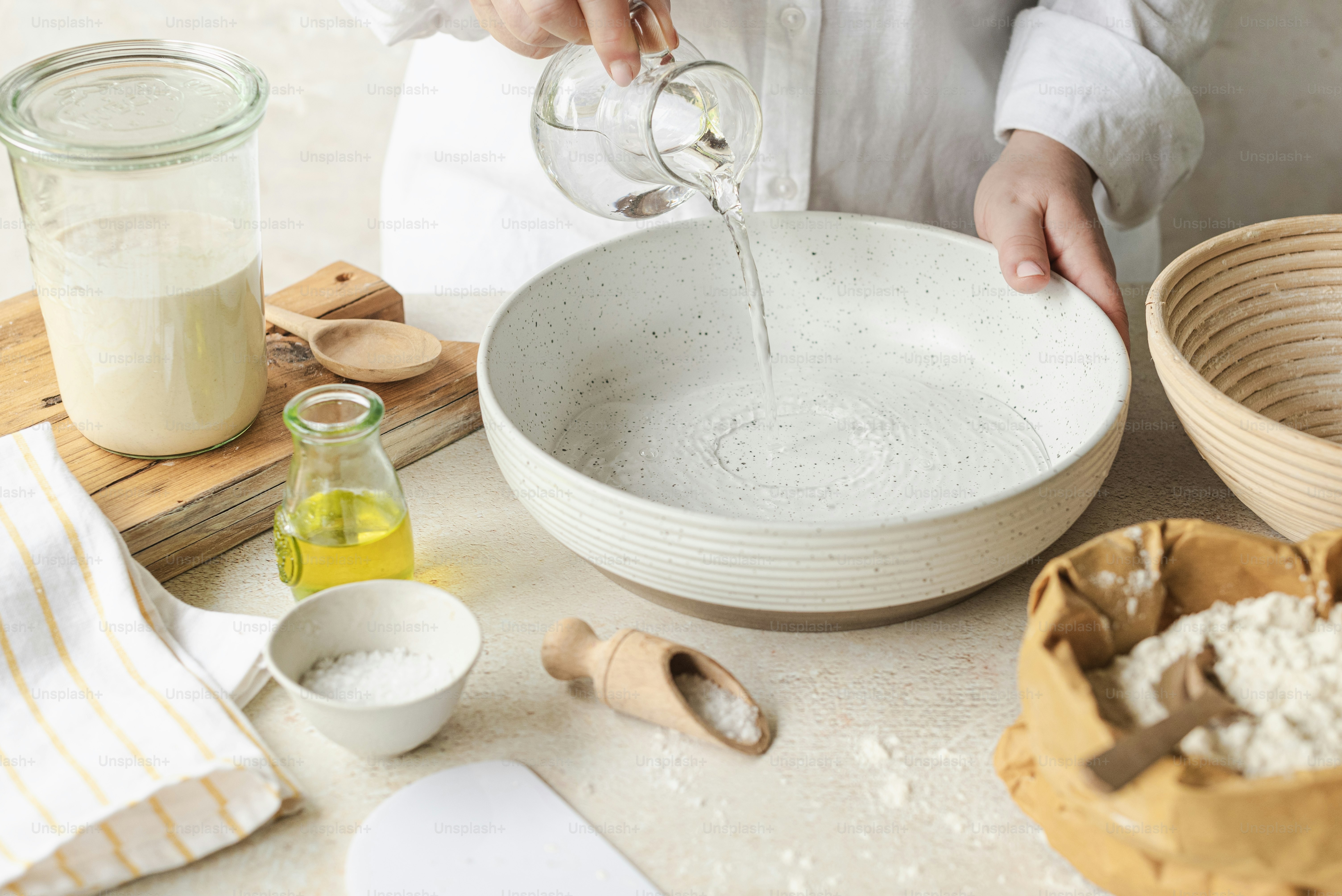 A person pouring something into a bowl on a table photo – Cooking Image ...