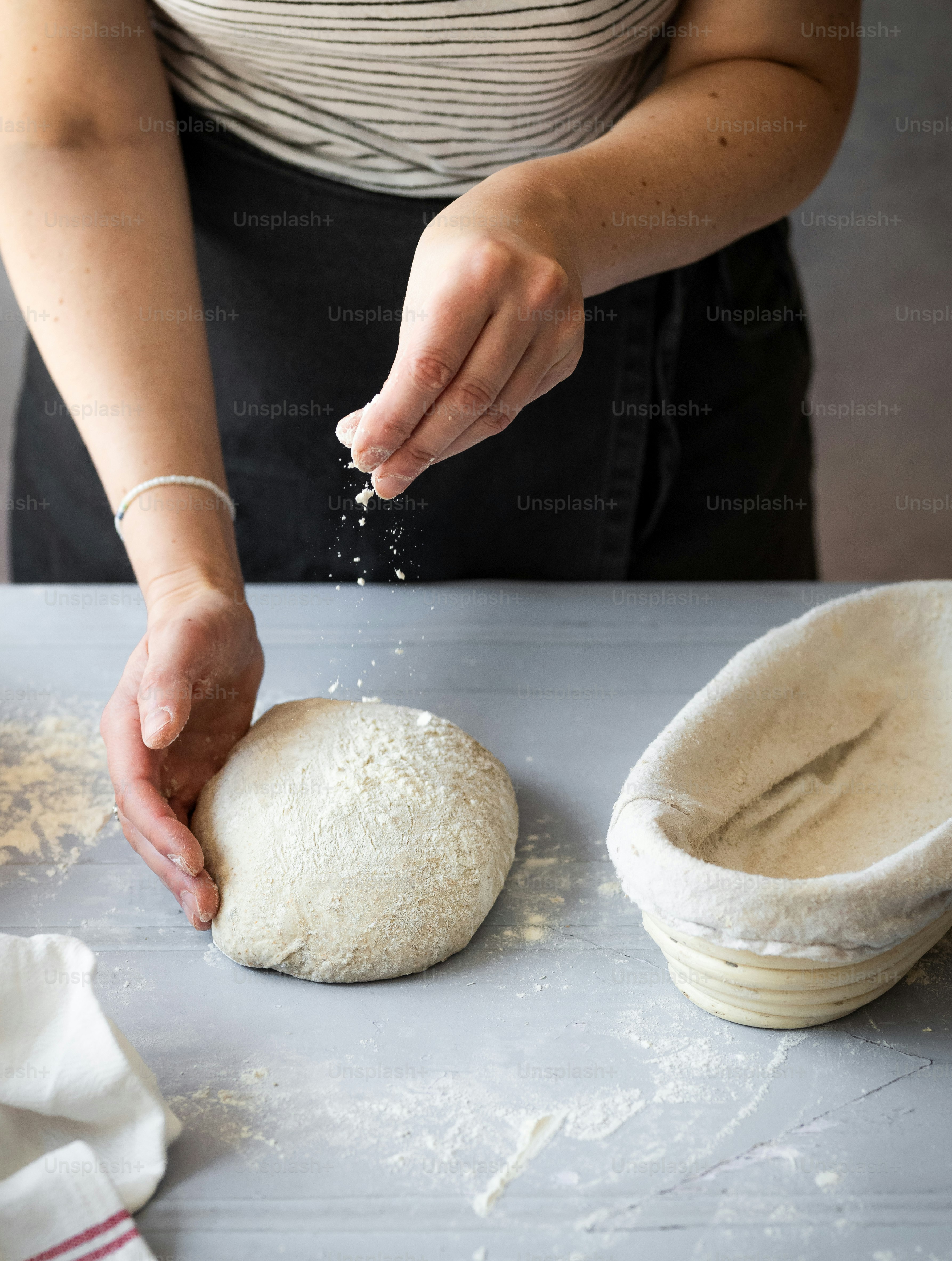 A woman sprinkling flour onto a ball of bread photo – Cooking Image on ...