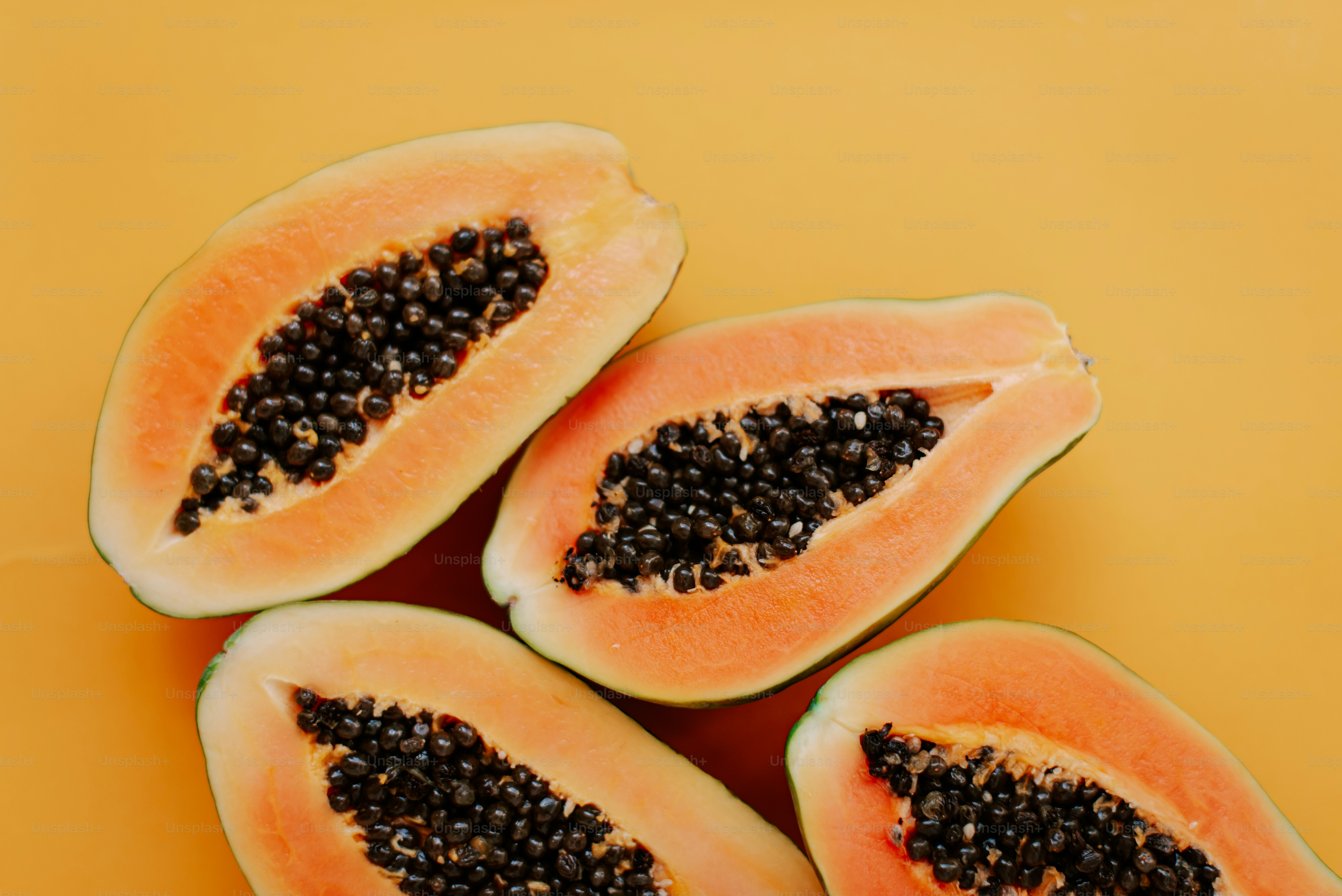 A group of cut up papaya on a yellow surface photo – Papaya Image on ...
