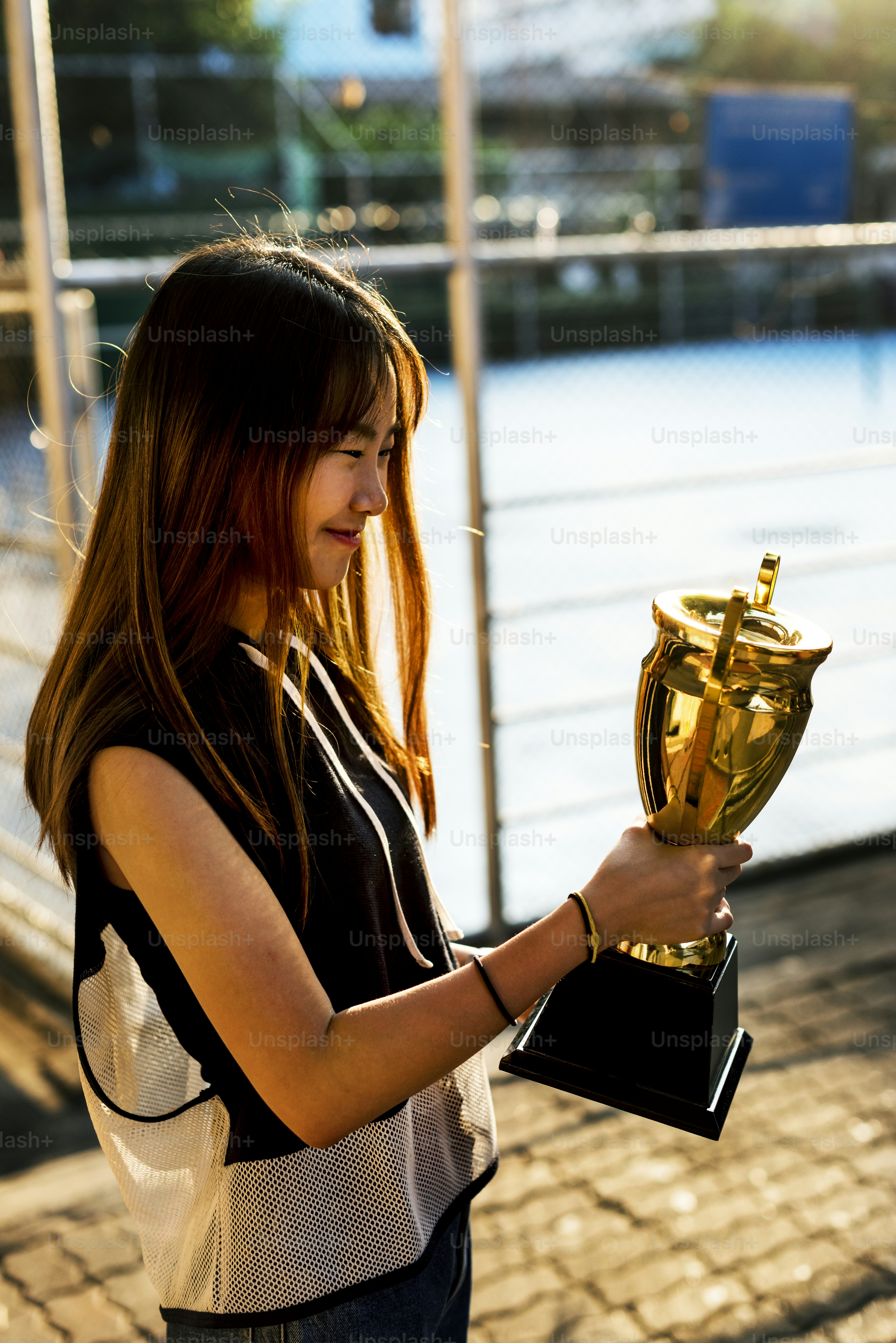 Asian teenage girl in sporty clothes holding a trophy outdoors photo ...