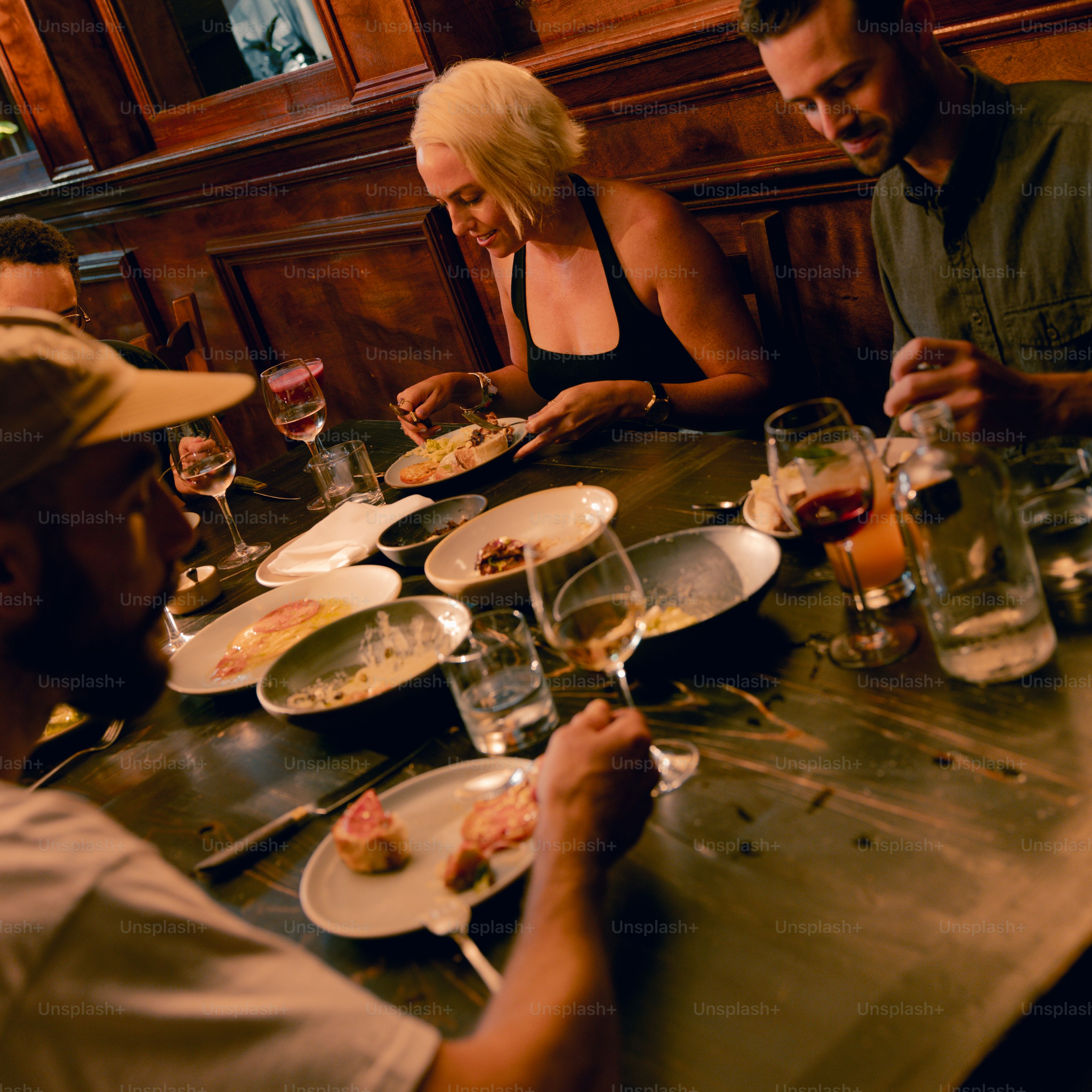 A group of people sitting around a table eating food photo – Dinner ...