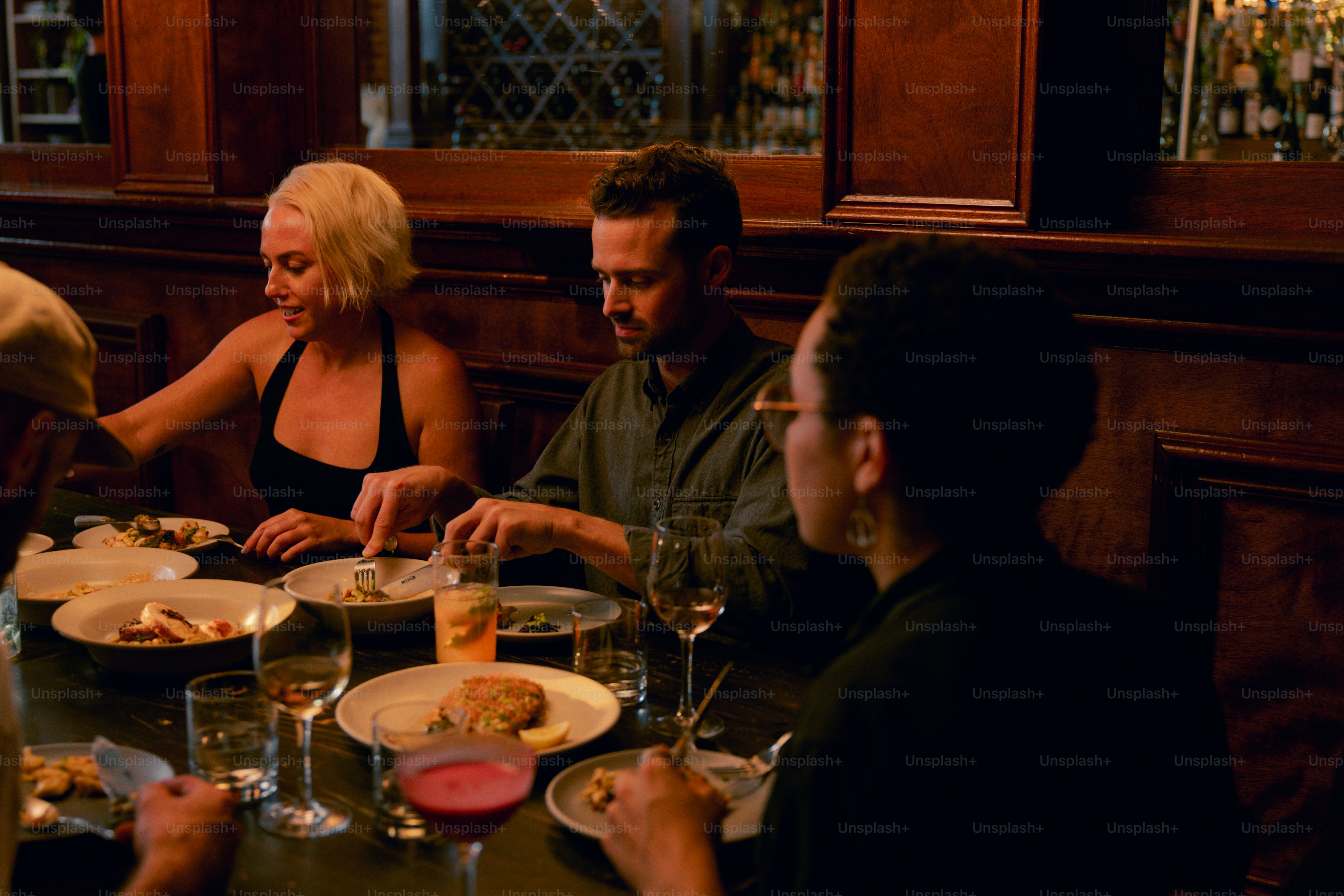 A group of people sitting around a table eating food photo – Dinner ...