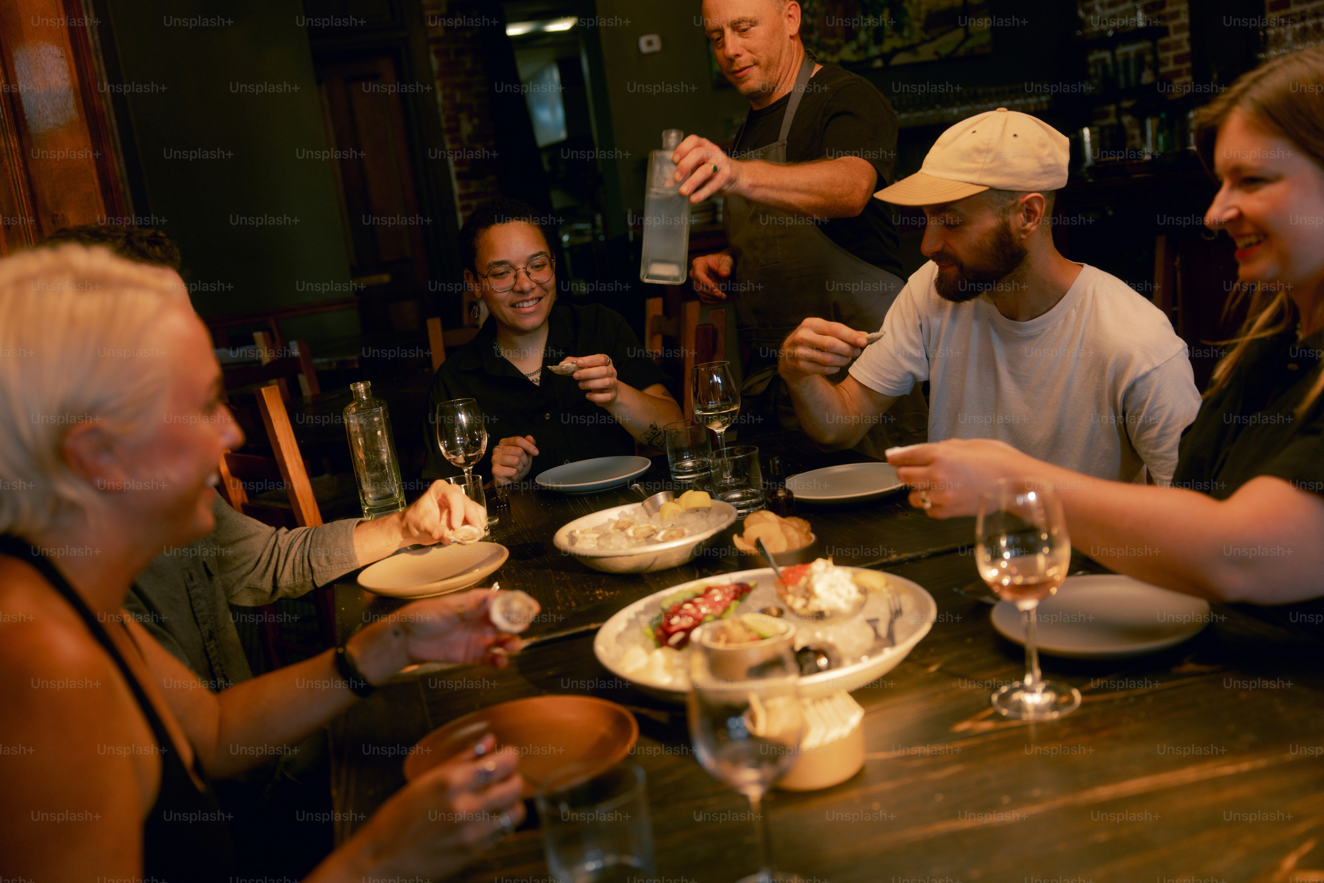 A group of people sitting around a table eating food photo – Dinner ...