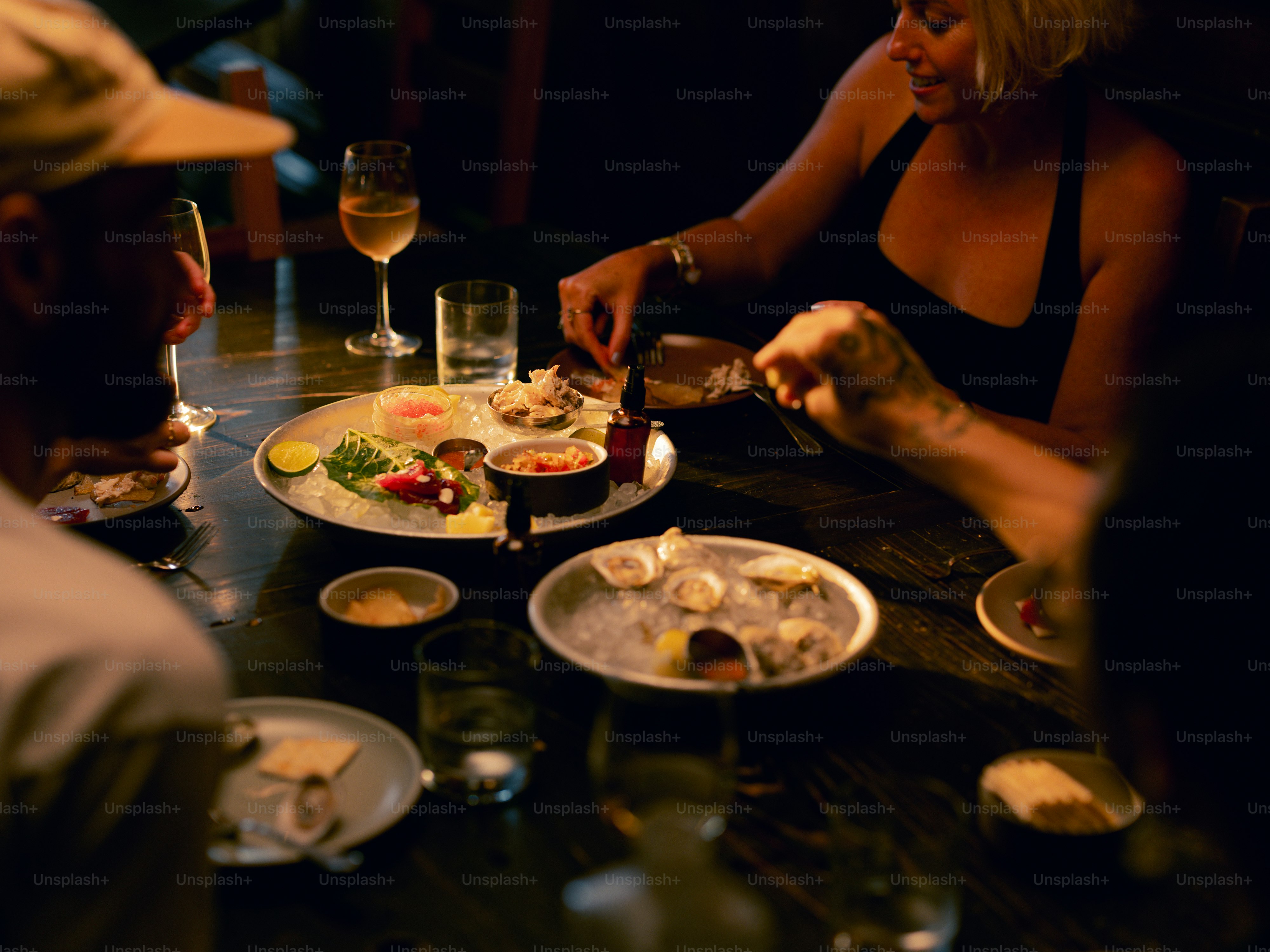 A group of people sitting around a table eating food photo – Dinner ...