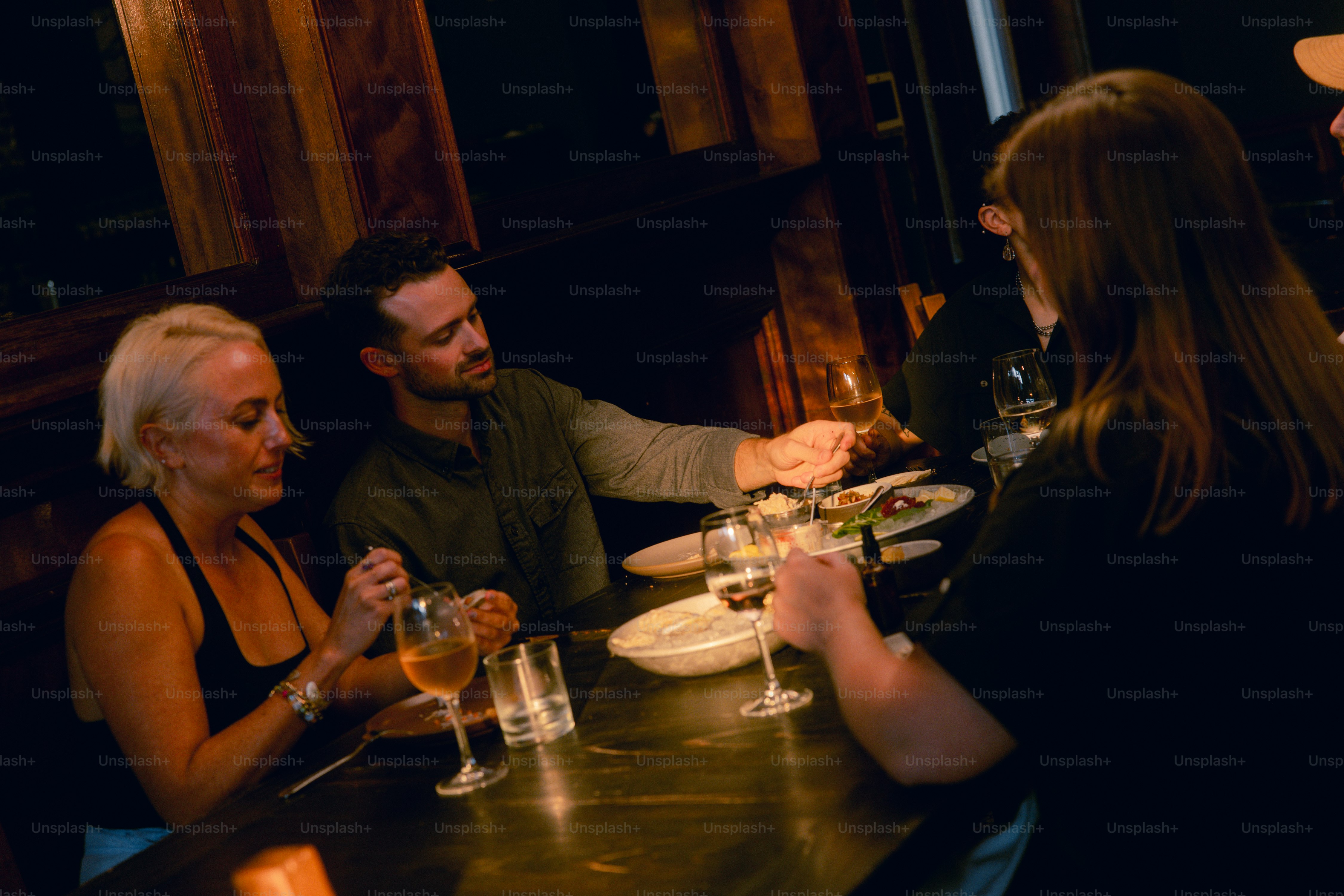A group of people sitting around a table photo – Dinner party Image on ...