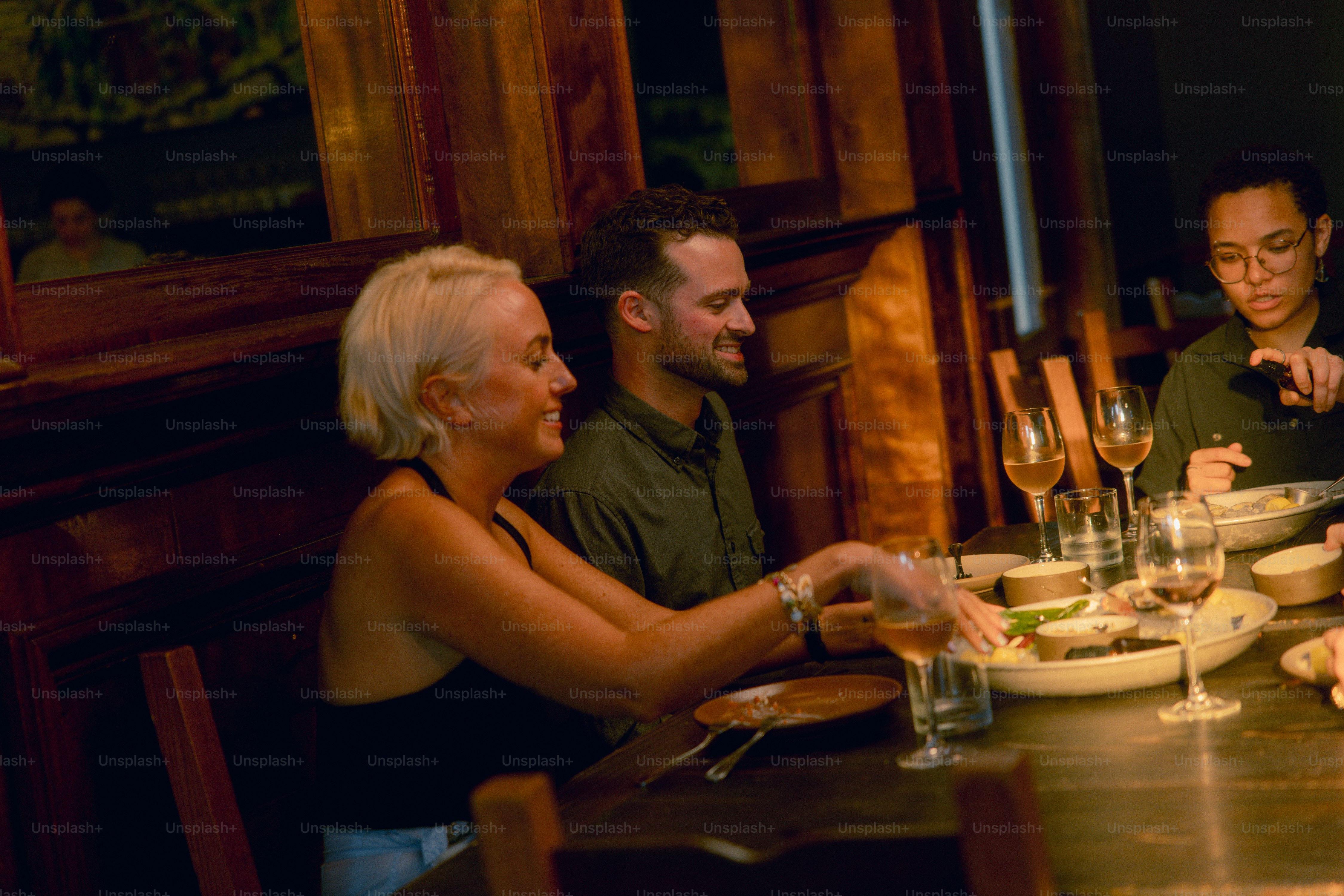 A group of people sitting around a dinner table photo – Restaurant ...