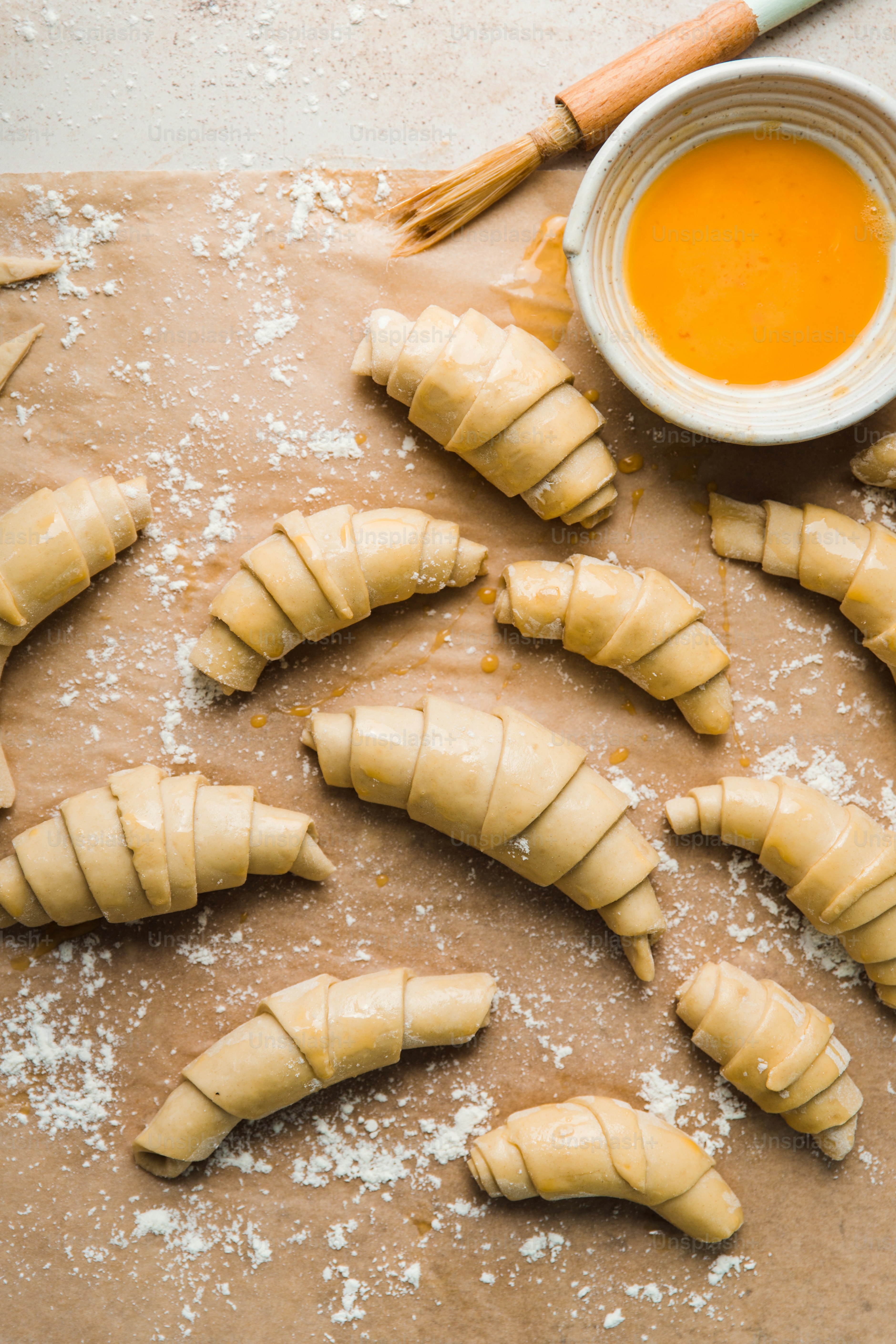 A table topped with pastries next to a bowl of orange liquid photo ...