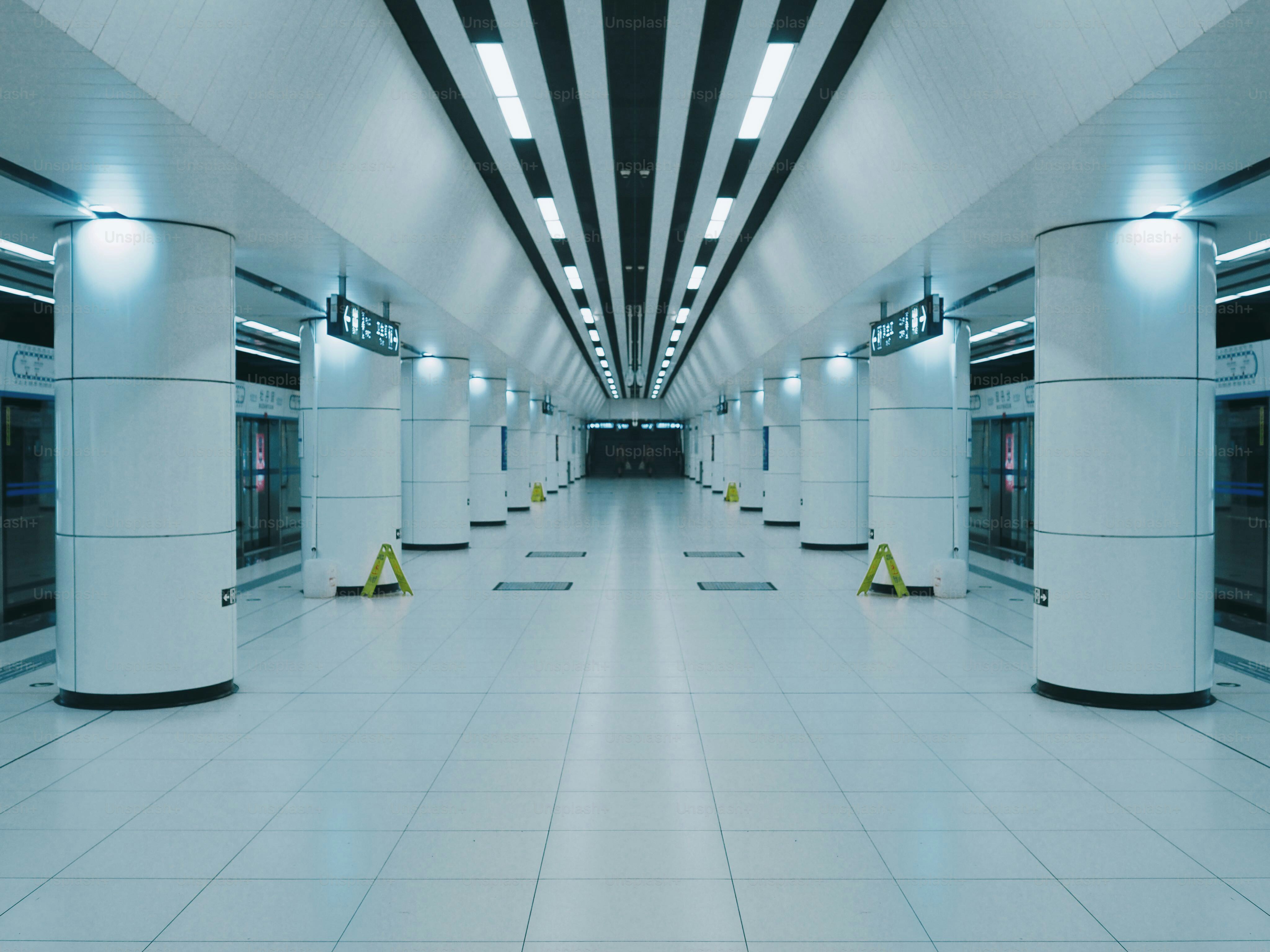 A long hallway with white walls and black and white striped ceiling ...