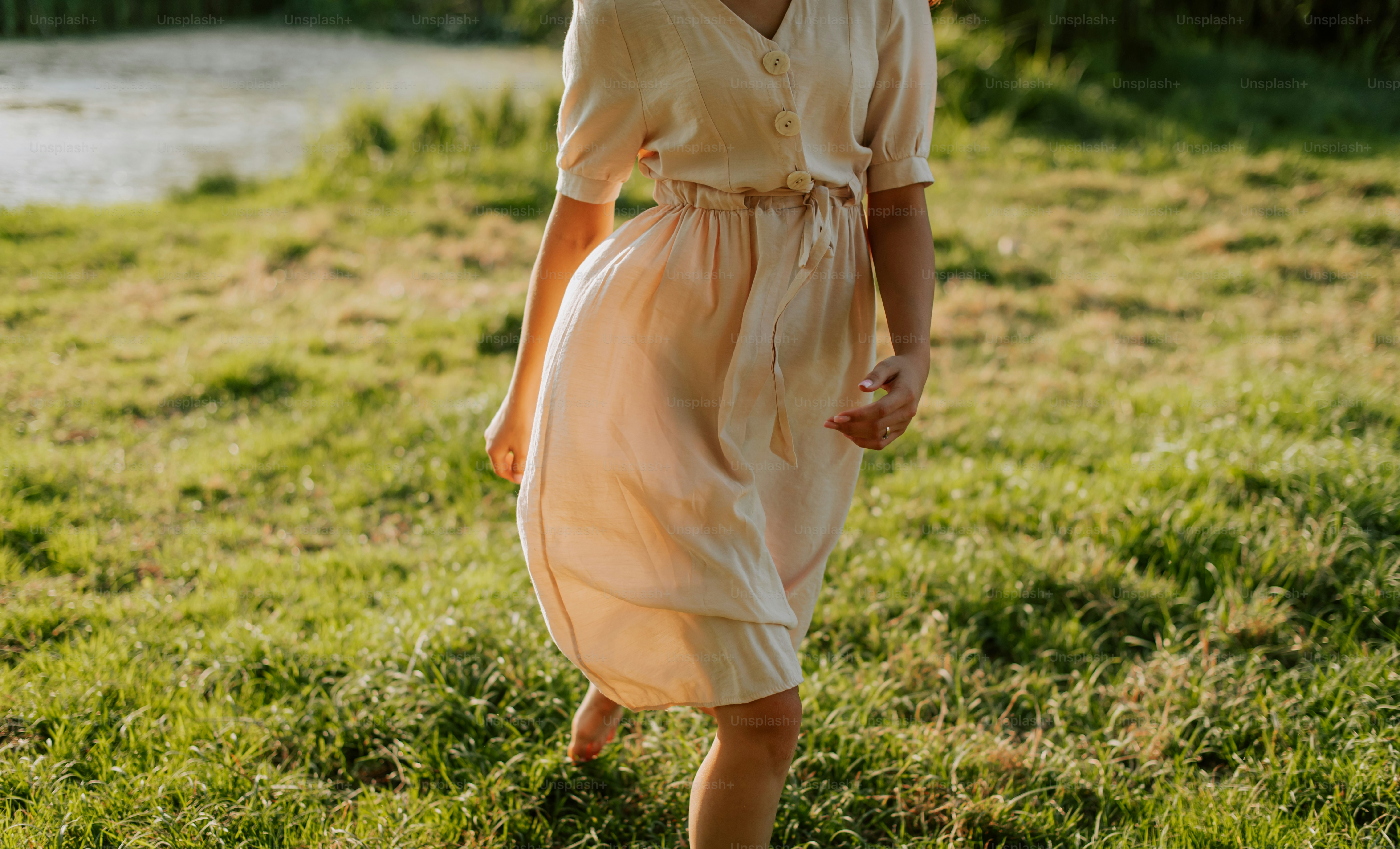 A woman walking across a lush green field next to a river photo ...