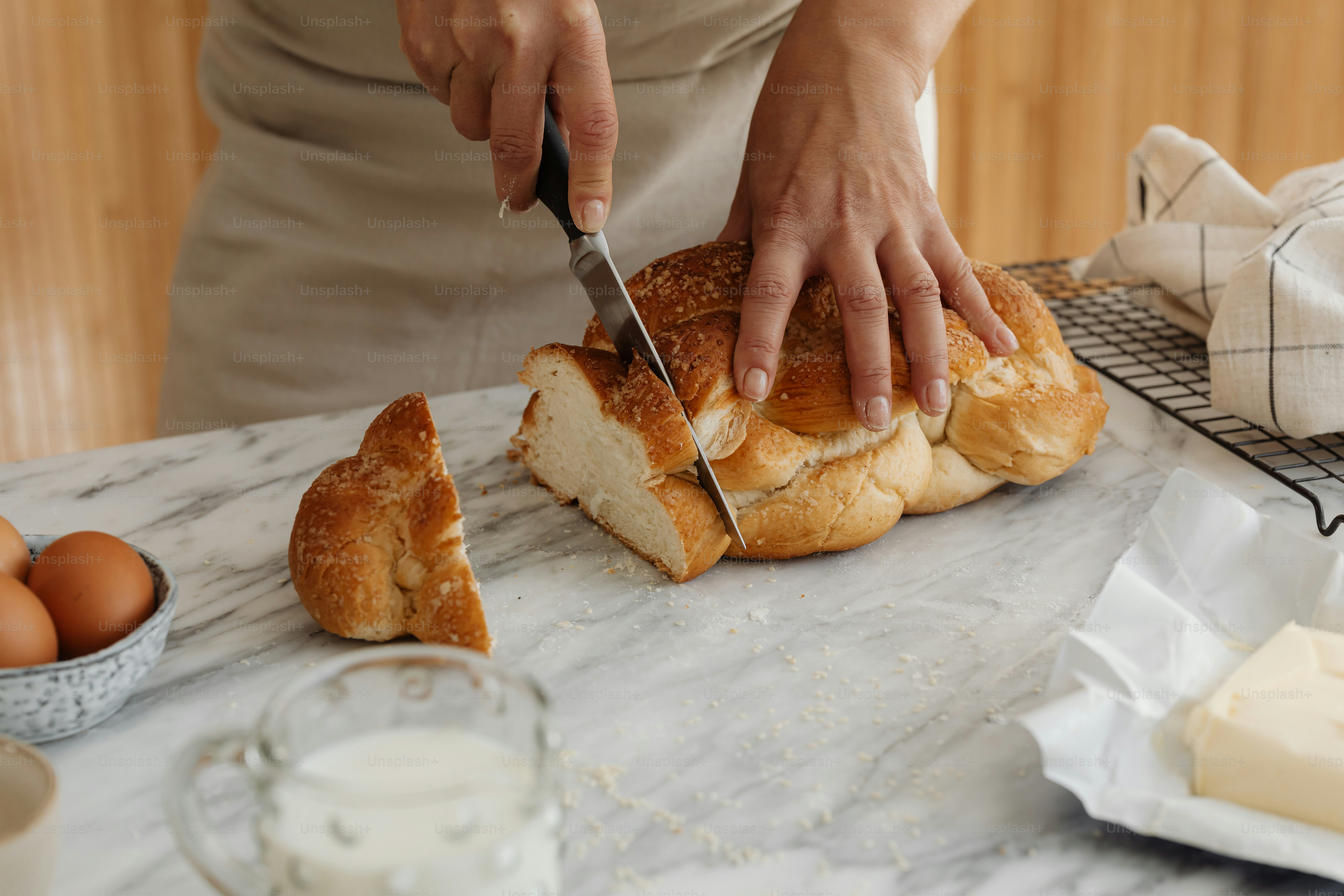 A person cutting a loaf of bread with a knife photo – Cooking Image on ...