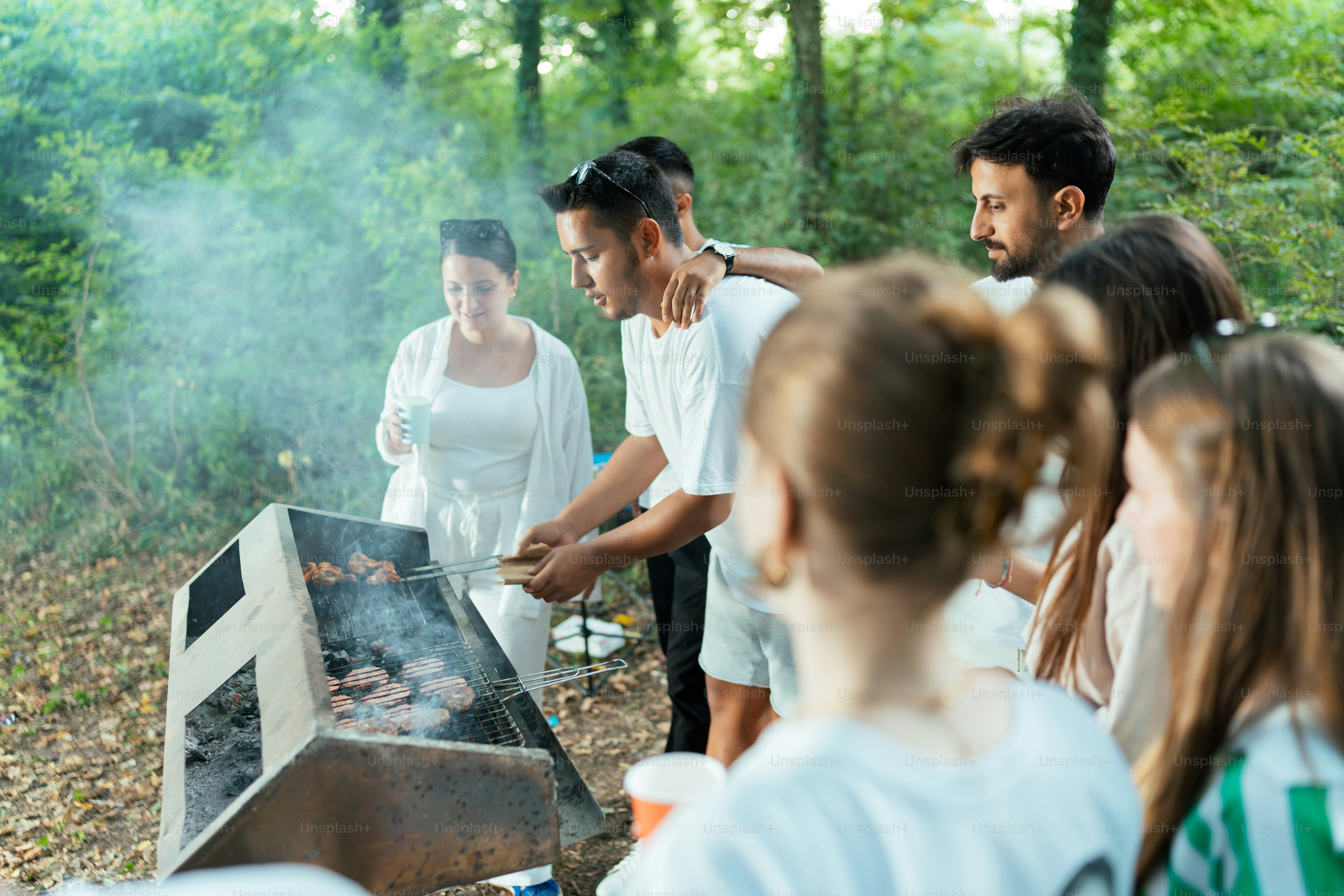 A group of people standing around a bbq grill photo – Barbecue Image on ...