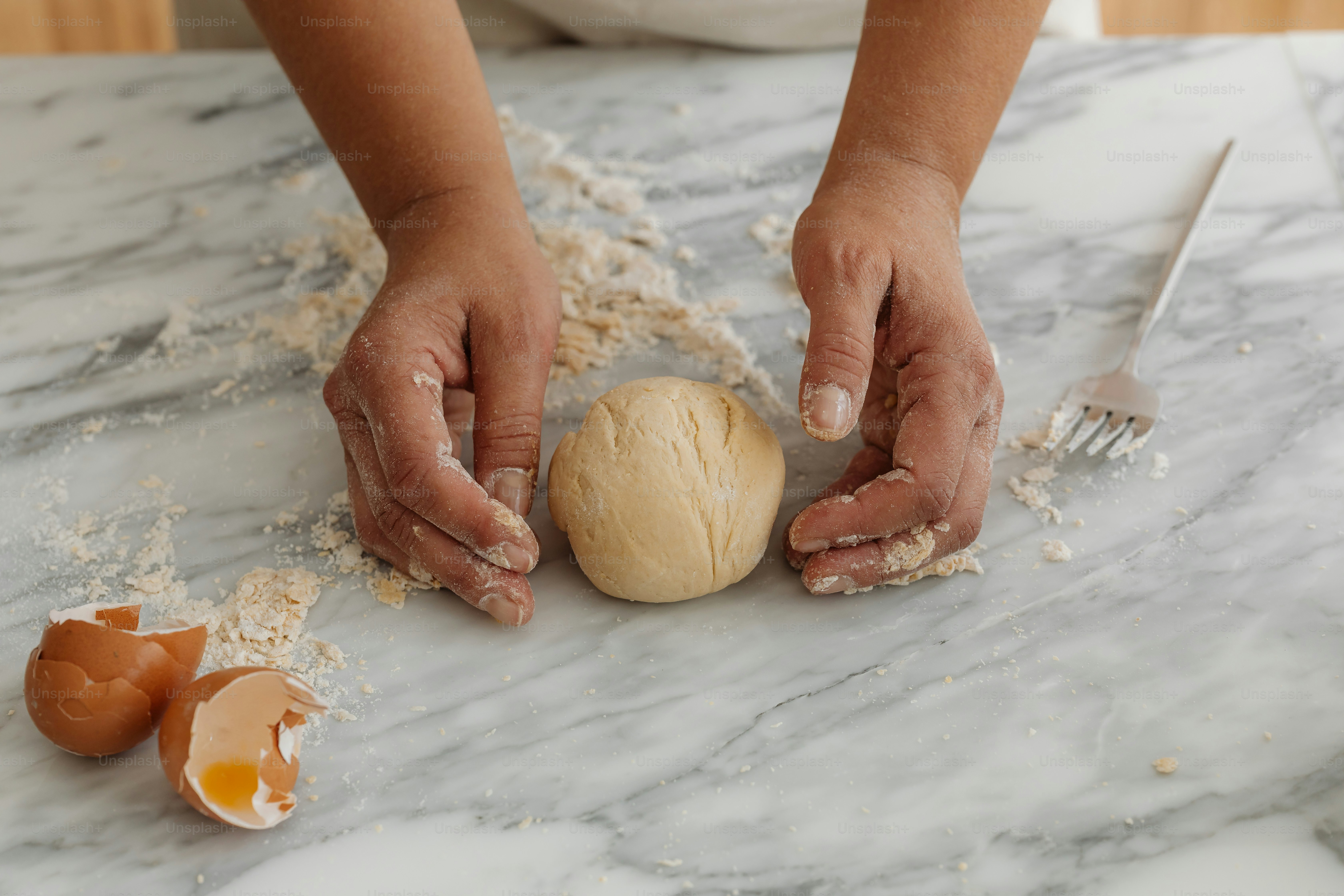 A person is kneading a ball of bread on a marble counter photo – Pasta ...