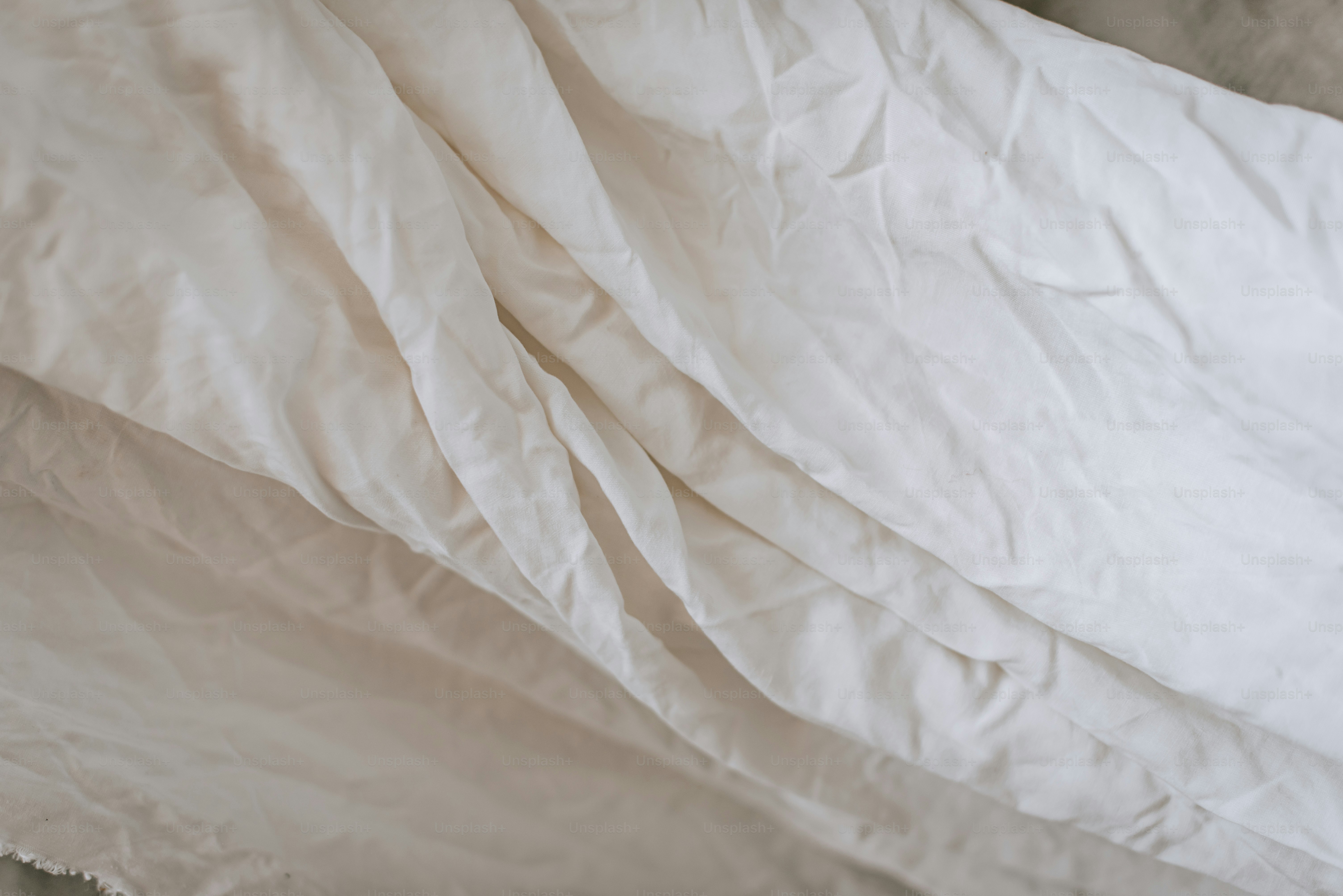 A pile of folded sheets sitting on top of a carpet photo – Neutral ...