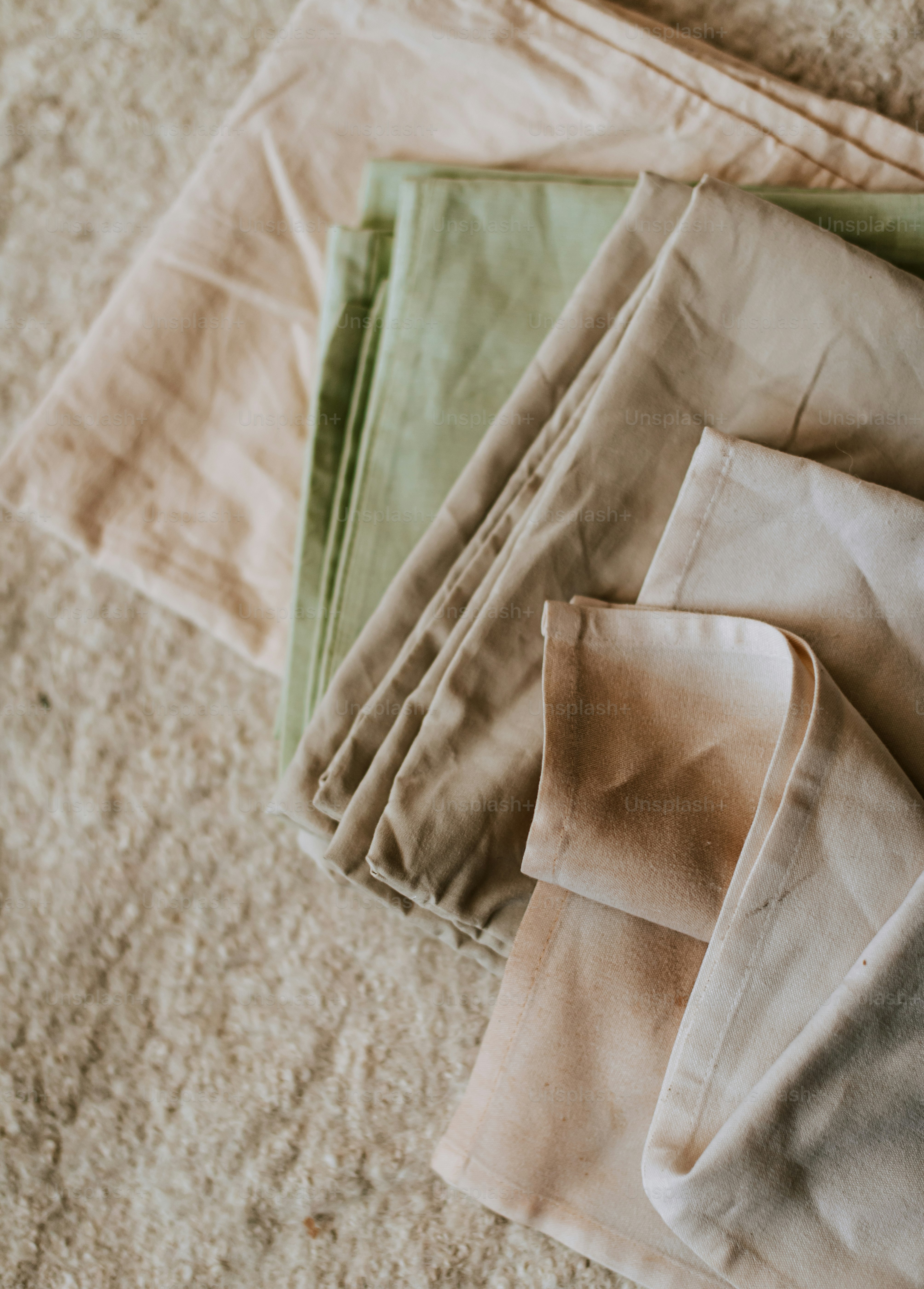 A pile of folded sheets sitting on top of a carpet photo – Neutral ...