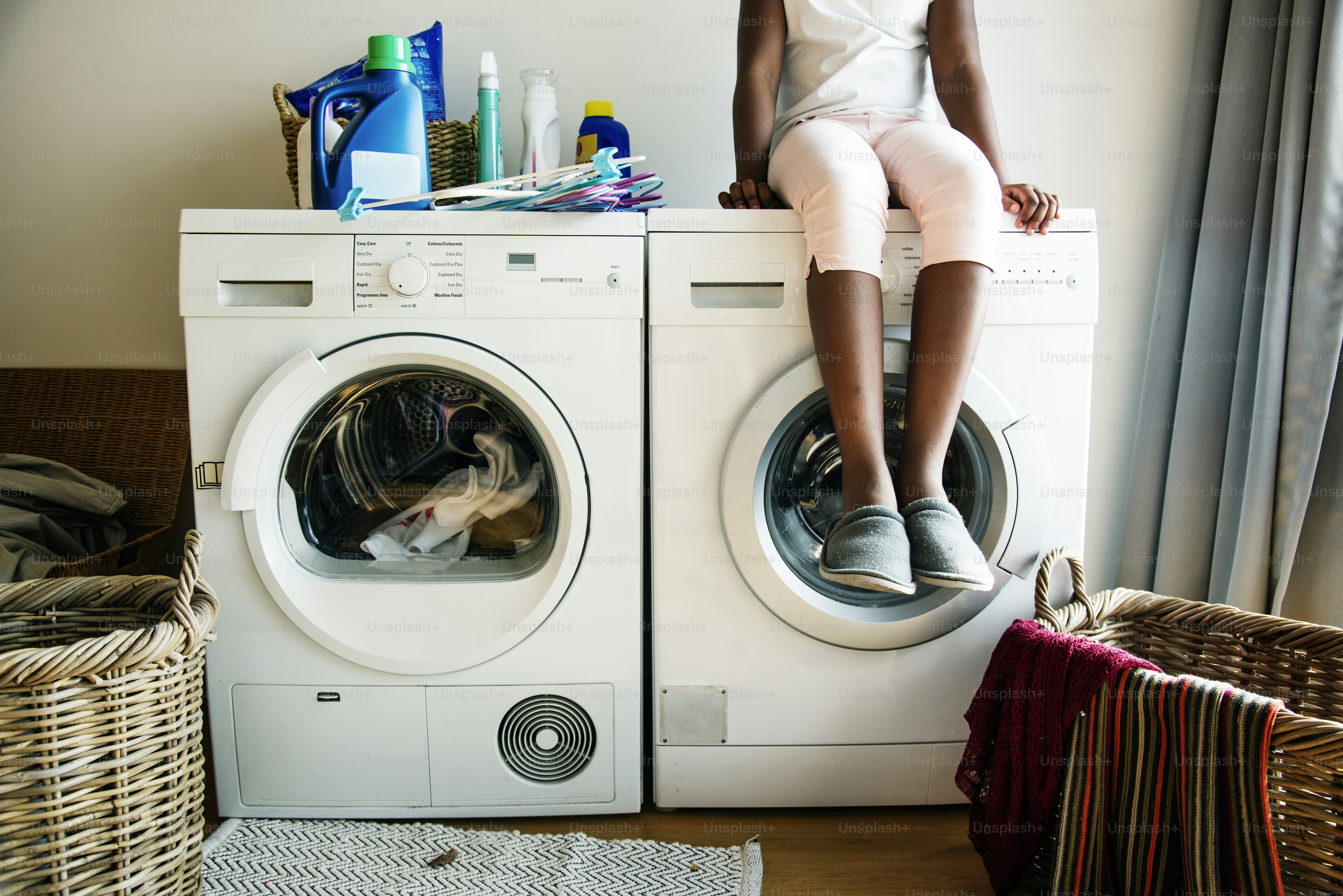 Young teen girl waiting for clothe to be washed from washing machine ...