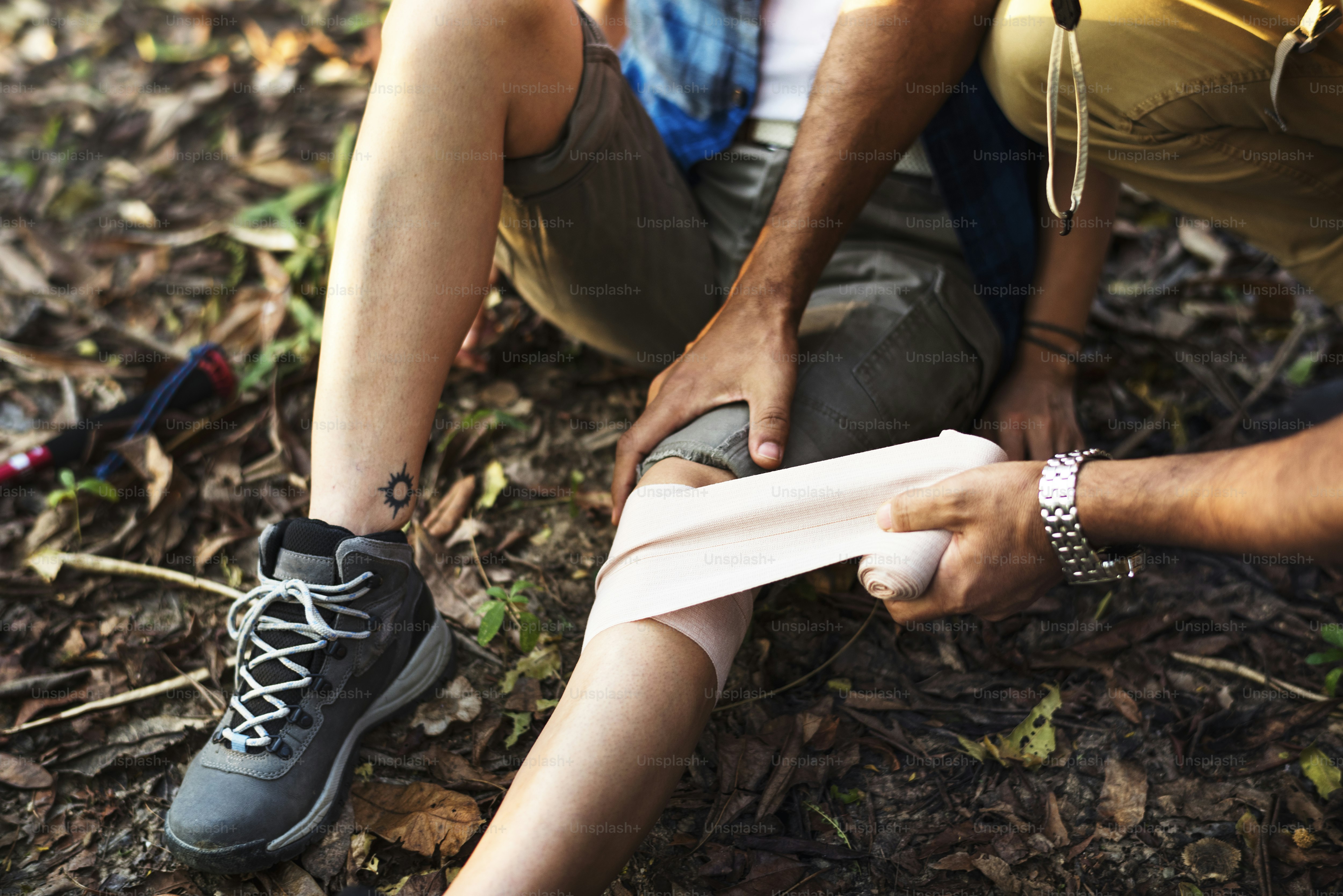 Man putting bandage on his partner's knee in the jungle photo – Couple ...